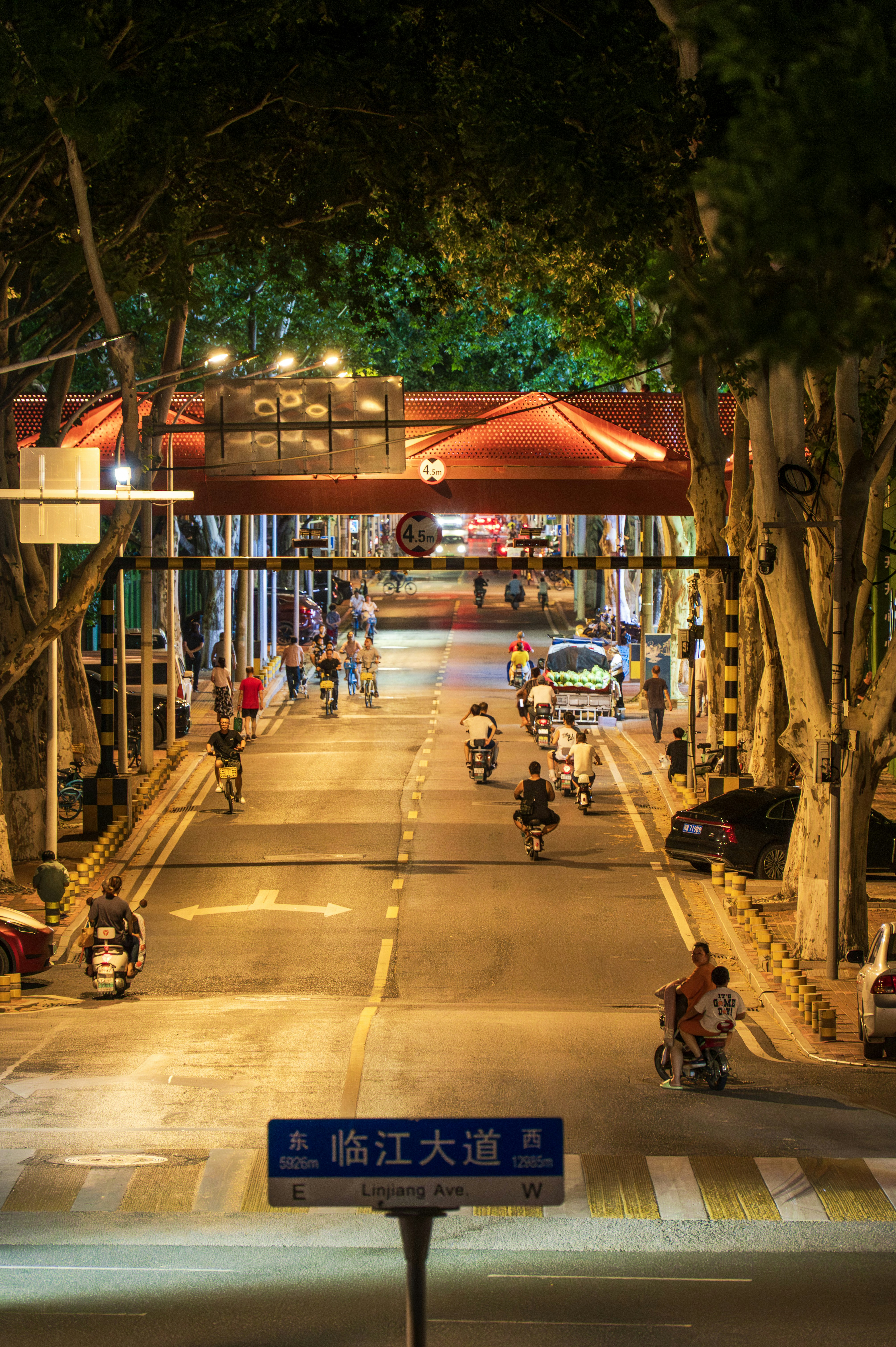 Amber Arc Over Linjiang Ave: Night Riders Thread a Lantern-Lit City Street