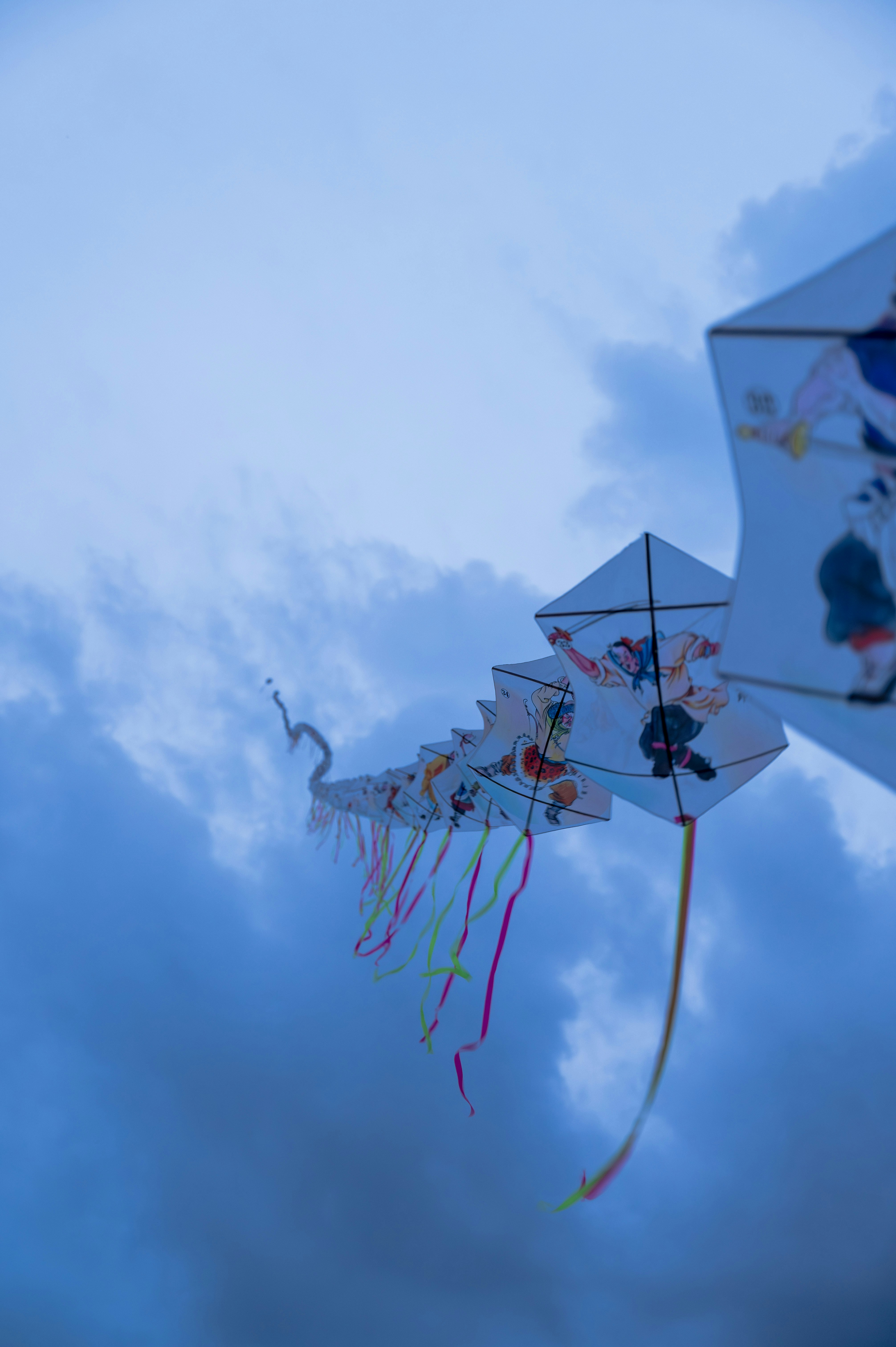 Ribbons in the Sky: A Line of Illustrated Kites Soaring Against a Pale Blue Backdrop
