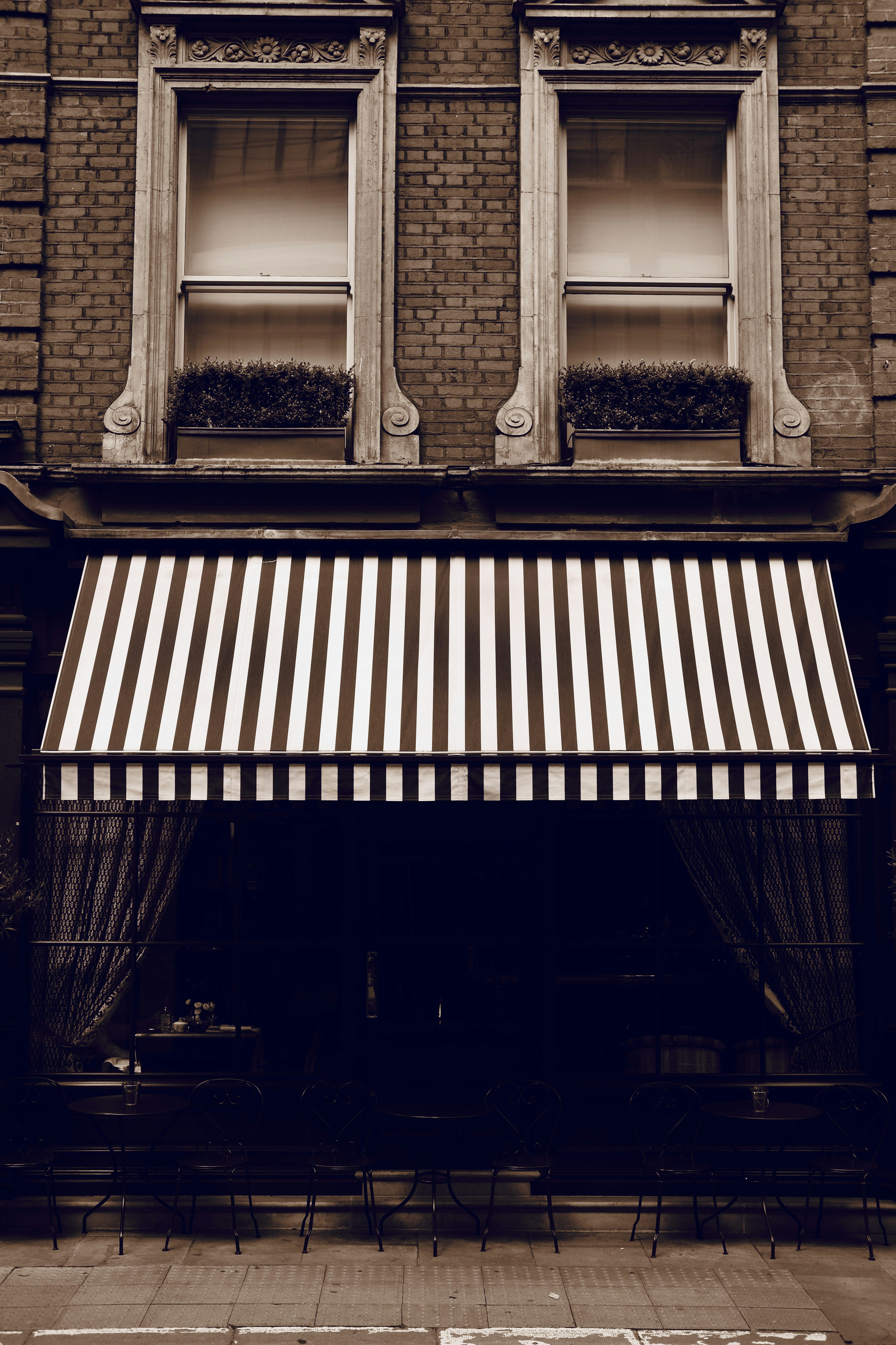 Striped Canopy at Dusk: A Quiet Café Beneath Brick Facades