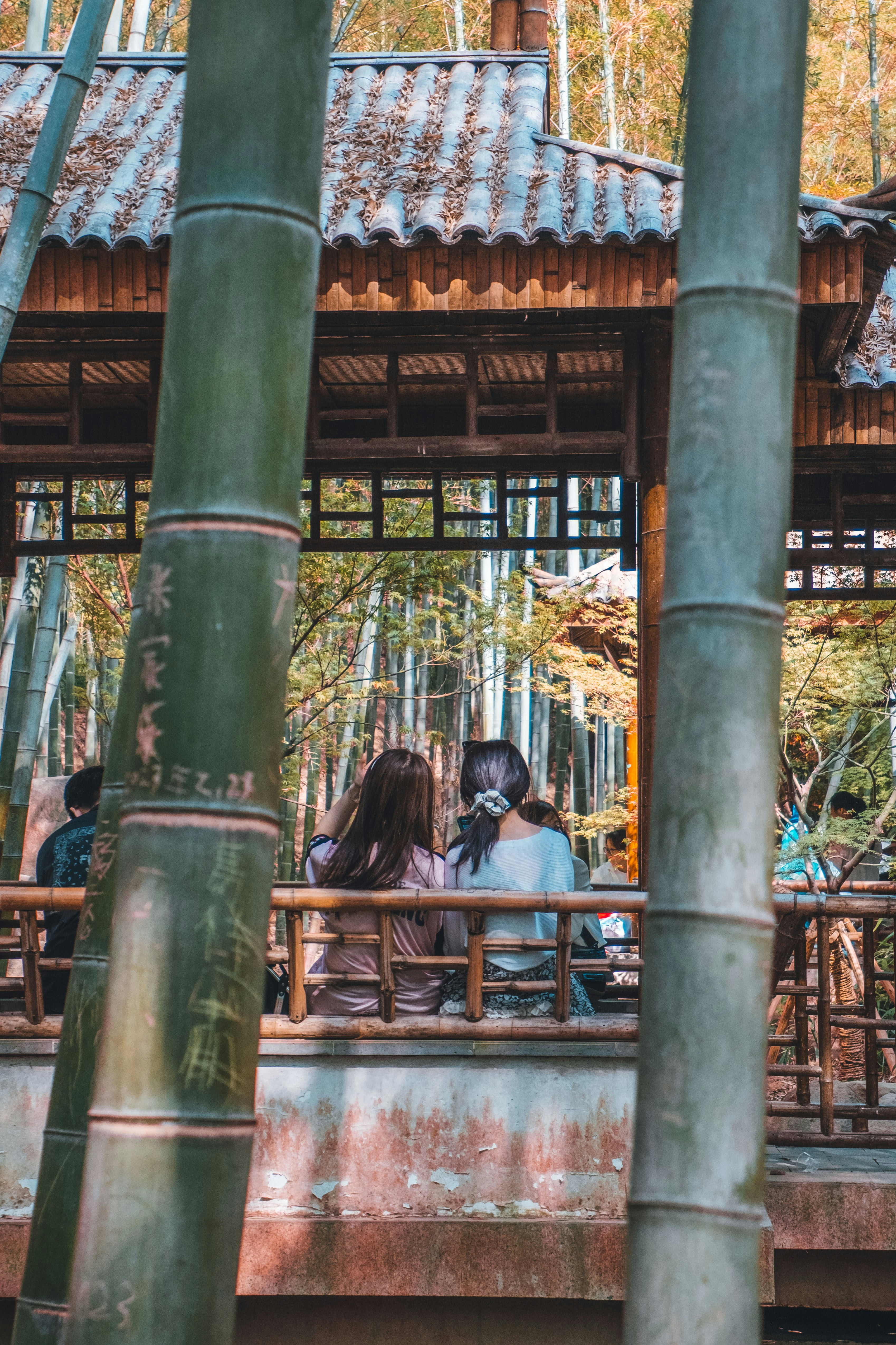 Two women sit in a bamboo gazebo.