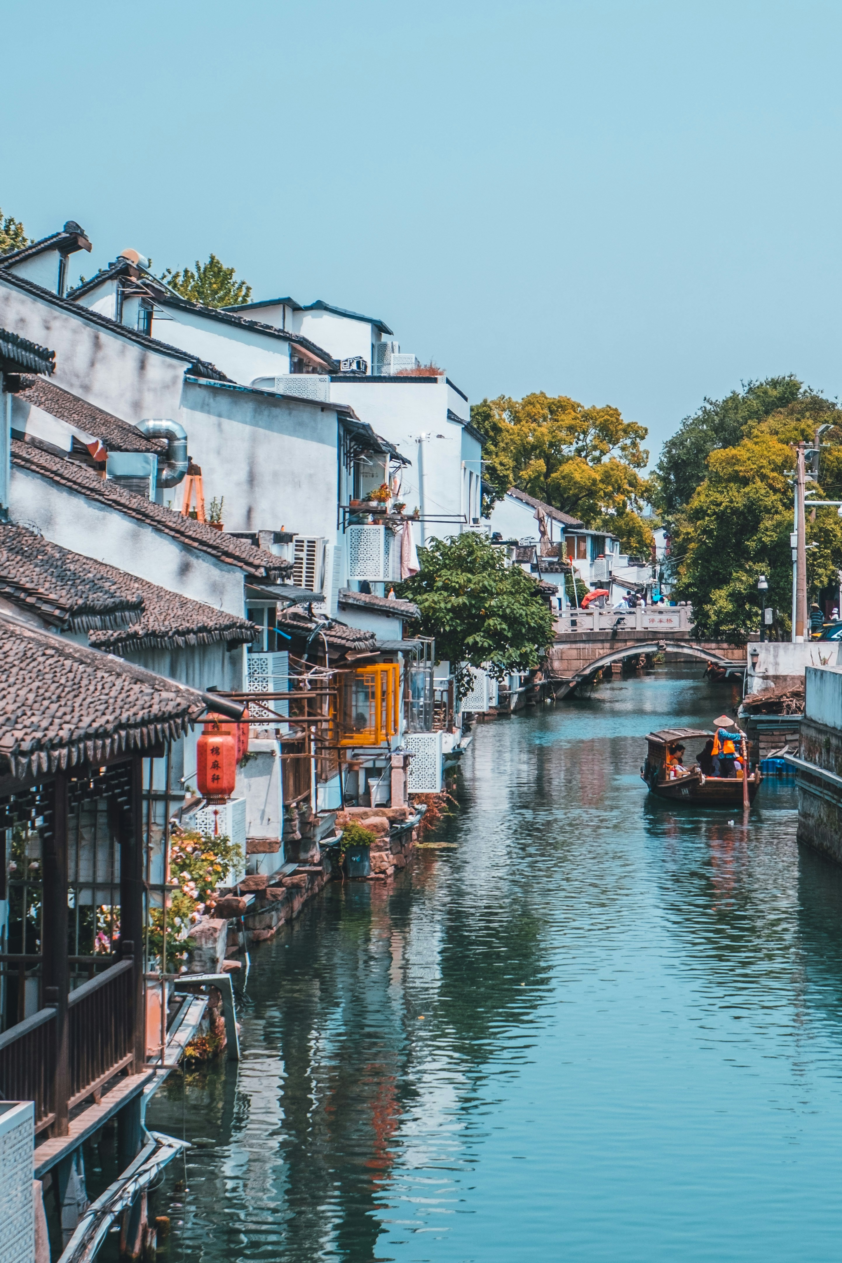 Suzhou City in China, Jiangsu. | Houses line a river, with a boat passing through.