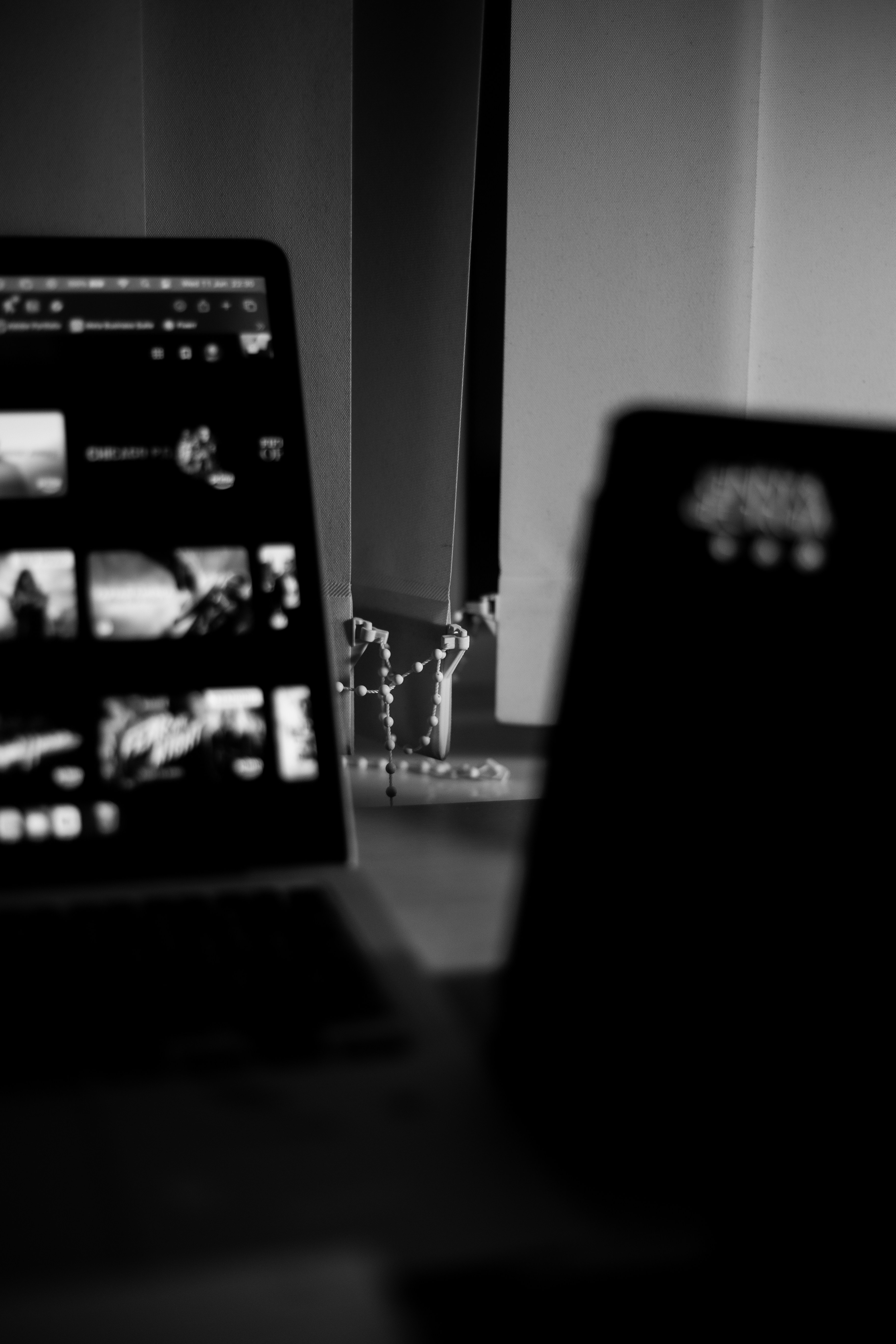 A monochromatic workspace featuring a laptop with a blurred screen and a delicate sculpture in the background, evoking a sense of artistic contemplation.