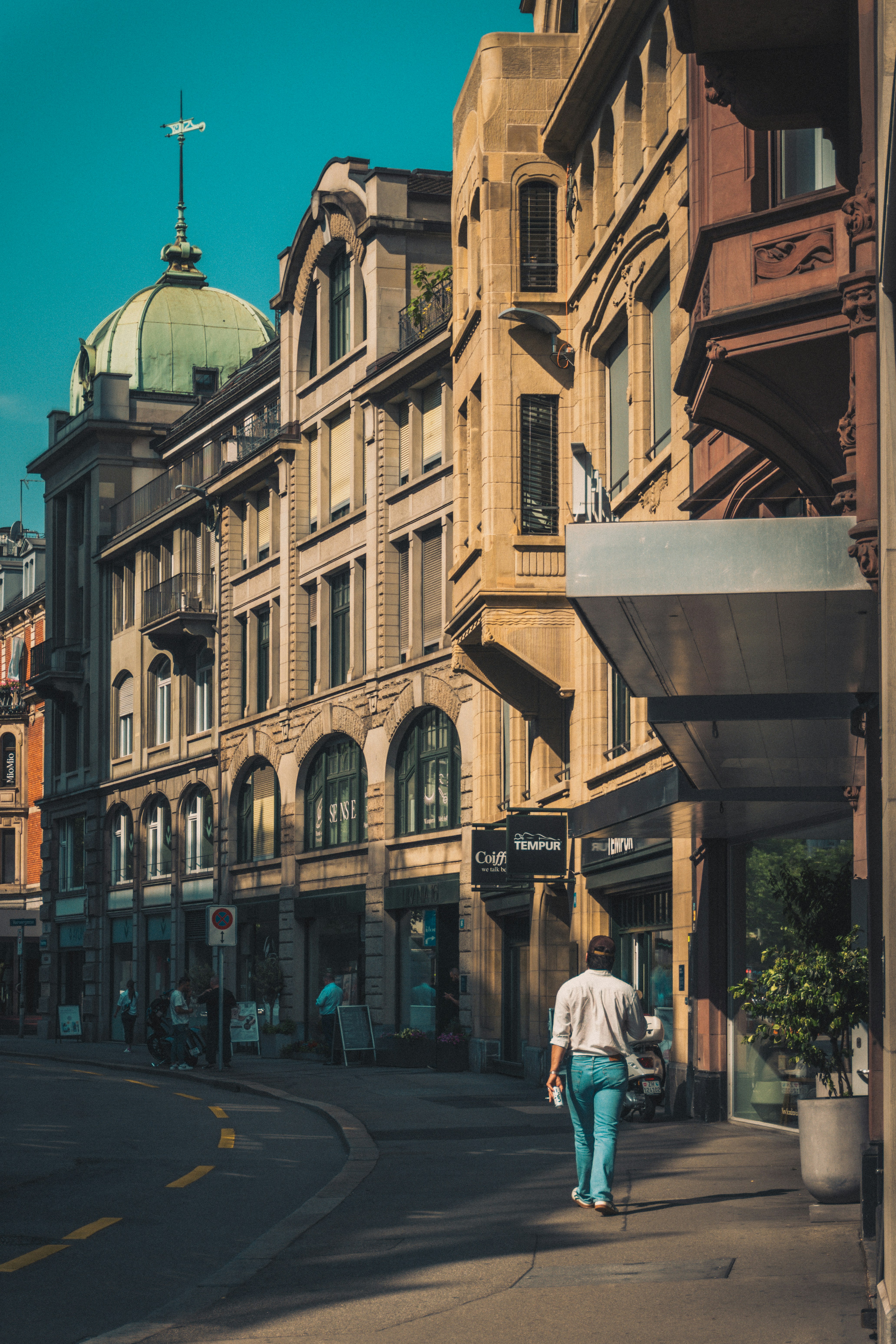 A man walks down a street with buildings.