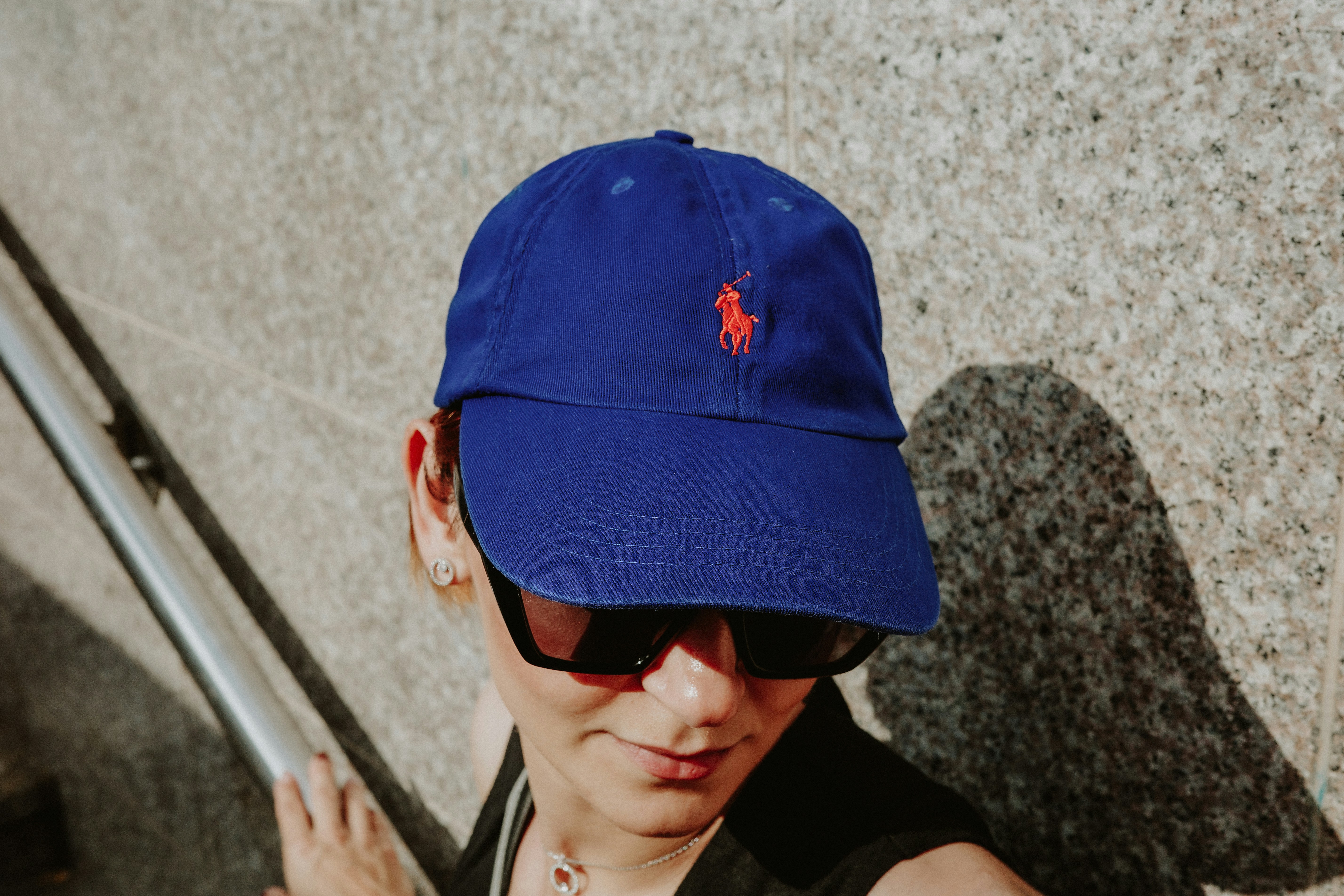 Person wearing a blue polo cap and sunglasses.