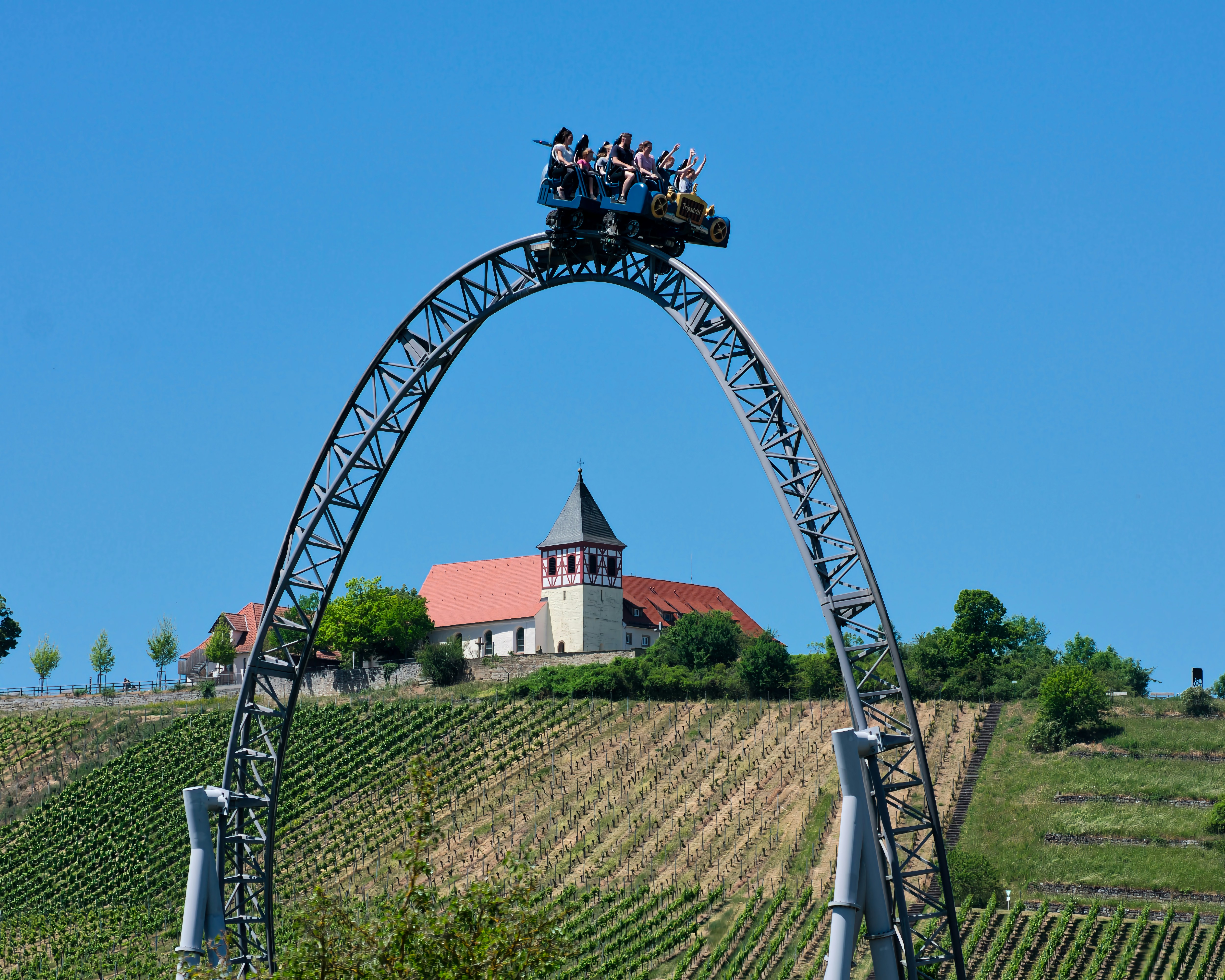 Arc Over the Vineyard: Train Cresting a Steel Loop Against Blue Sky
