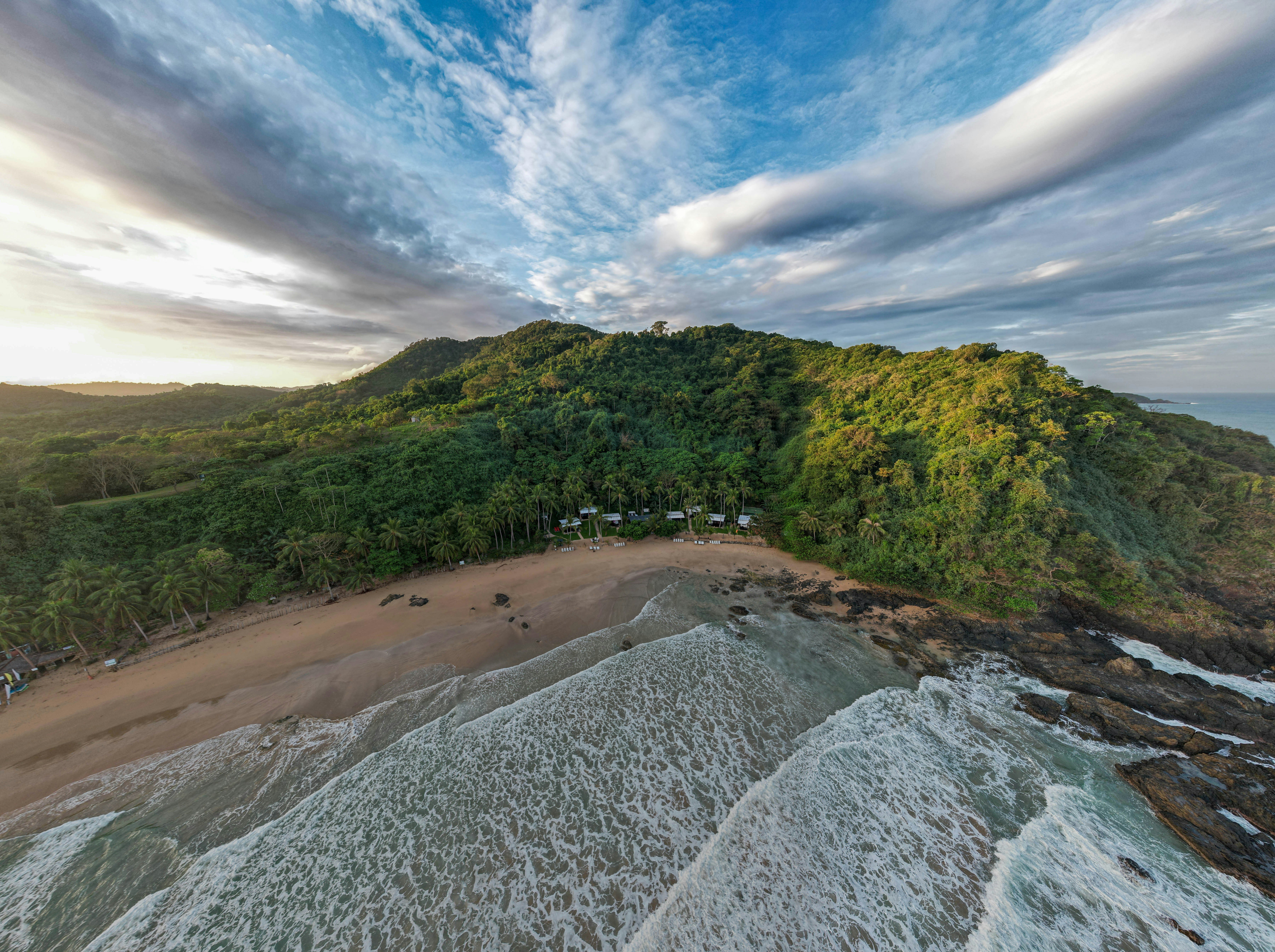 A tranquil beach nestled between lush greenery and rocky outcrops, showcasing gentle waves lapping at the shore.