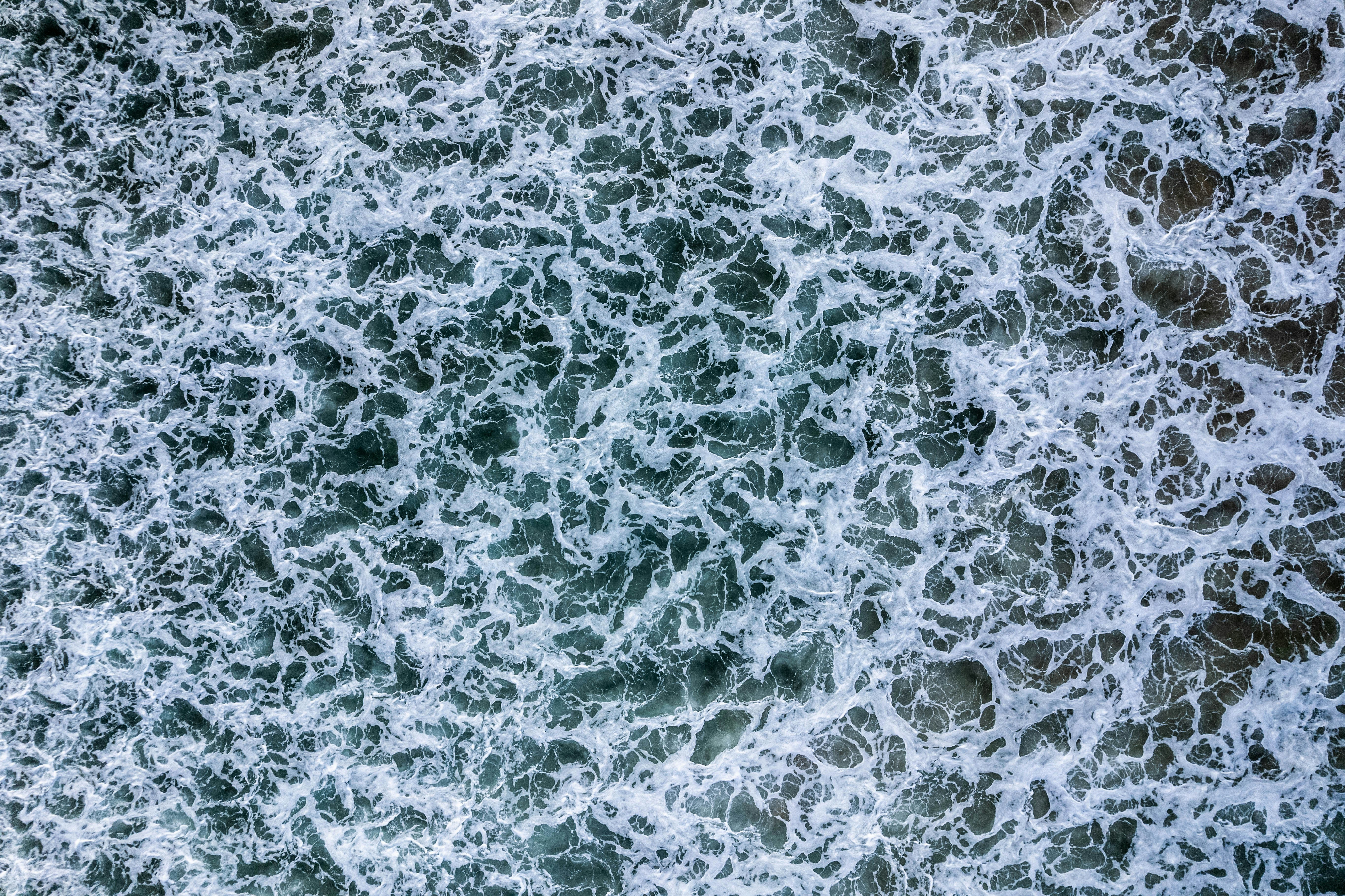 Waves crashing in the ocean form a foamy pattern.