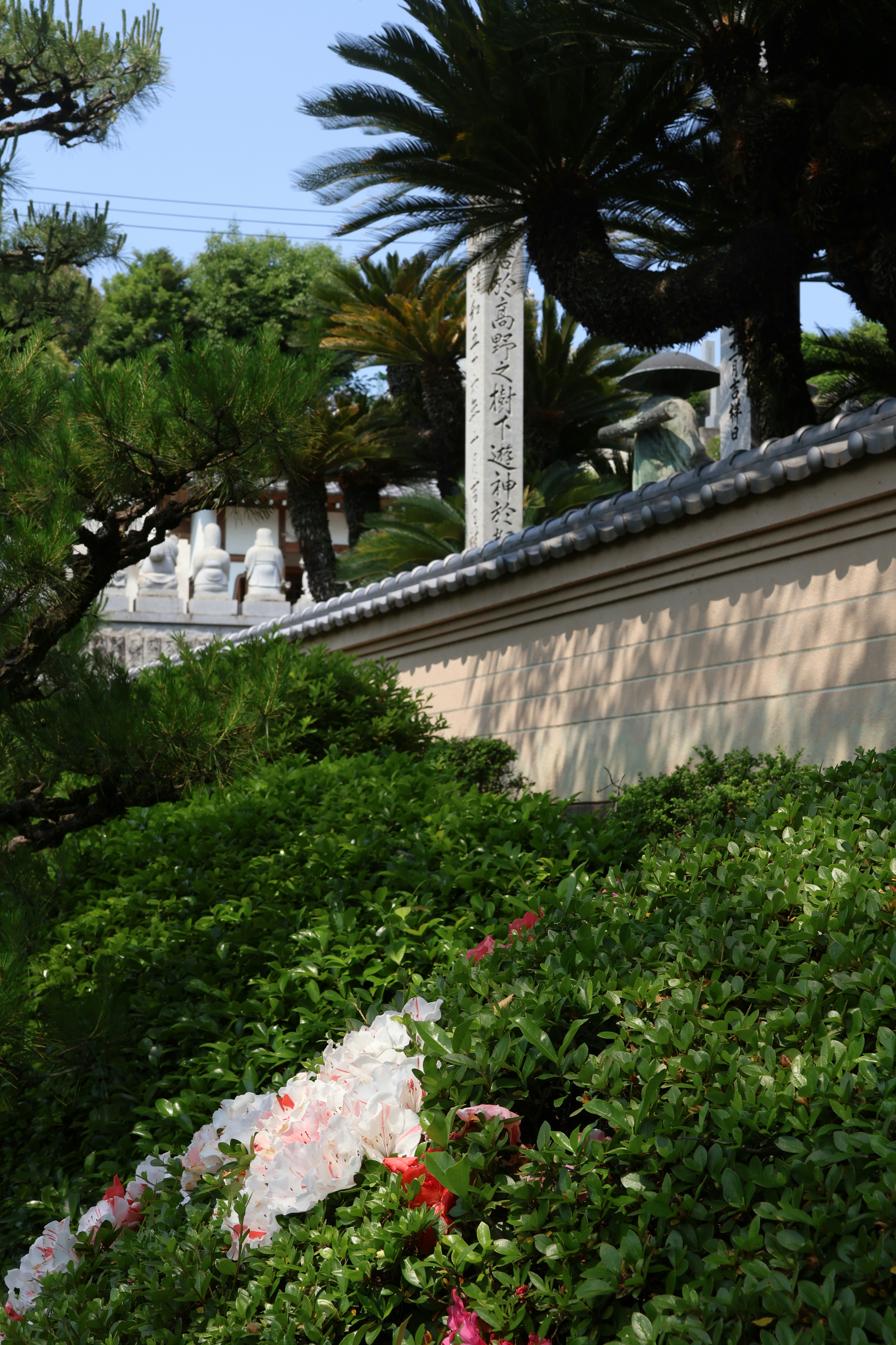 Inscribed Pillar Behind the Temple Wall Amid Lush Garden Blooms
