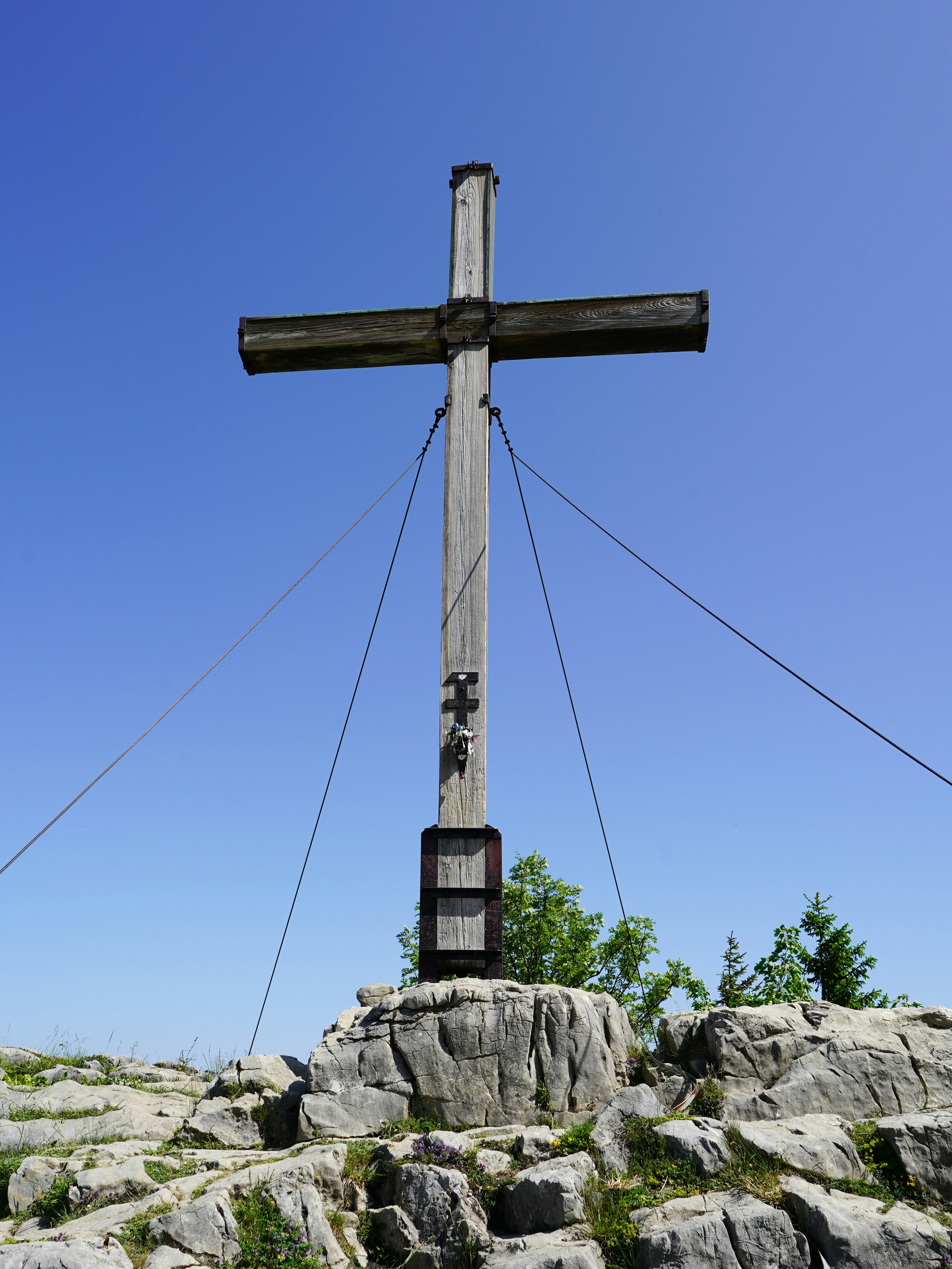 A wooden cross stands against a clear blue sky.