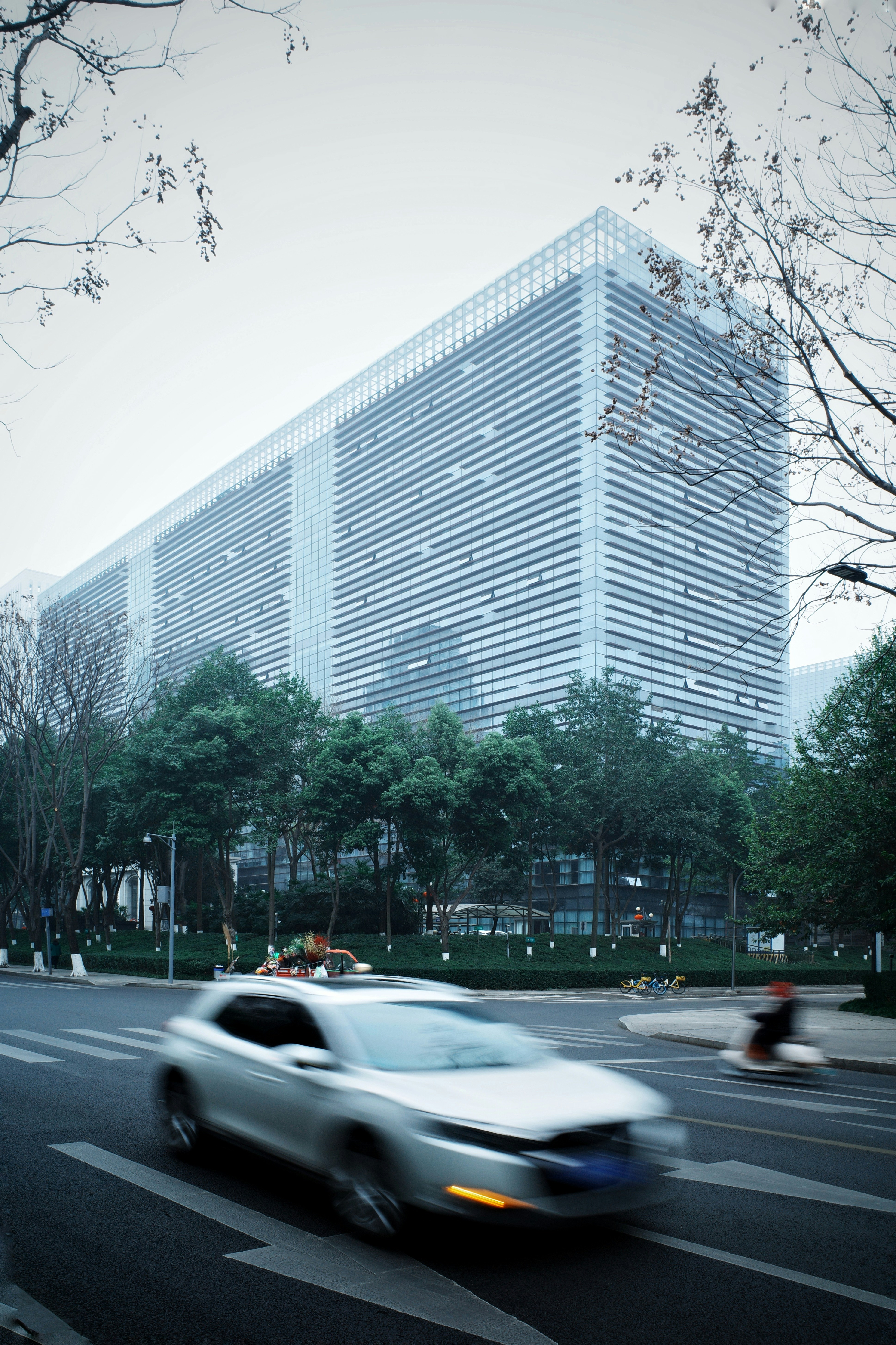 A modern building stands across the street. photo – Free Car Image on ...