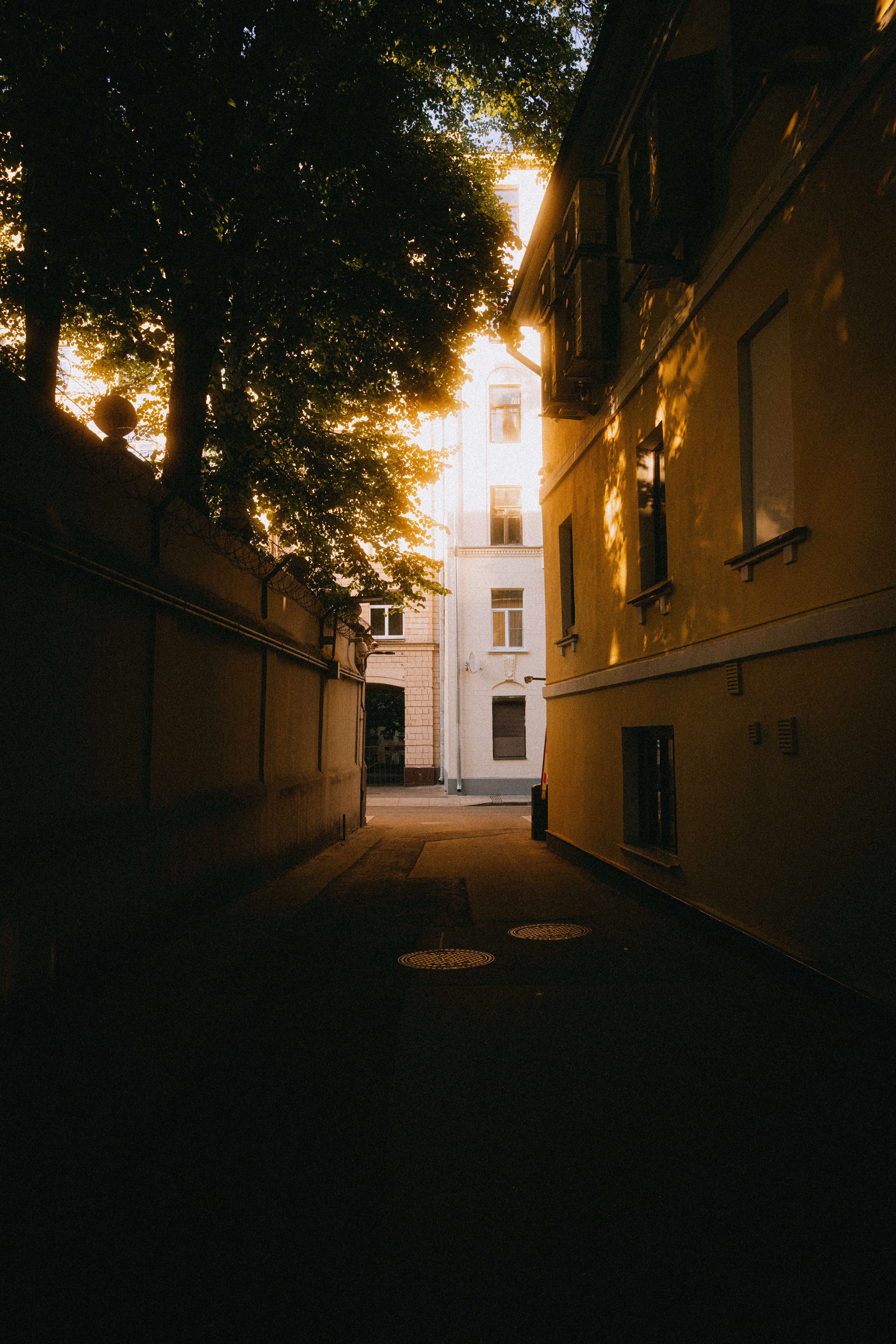 Sunlight illuminates a narrow alleyway between buildings.