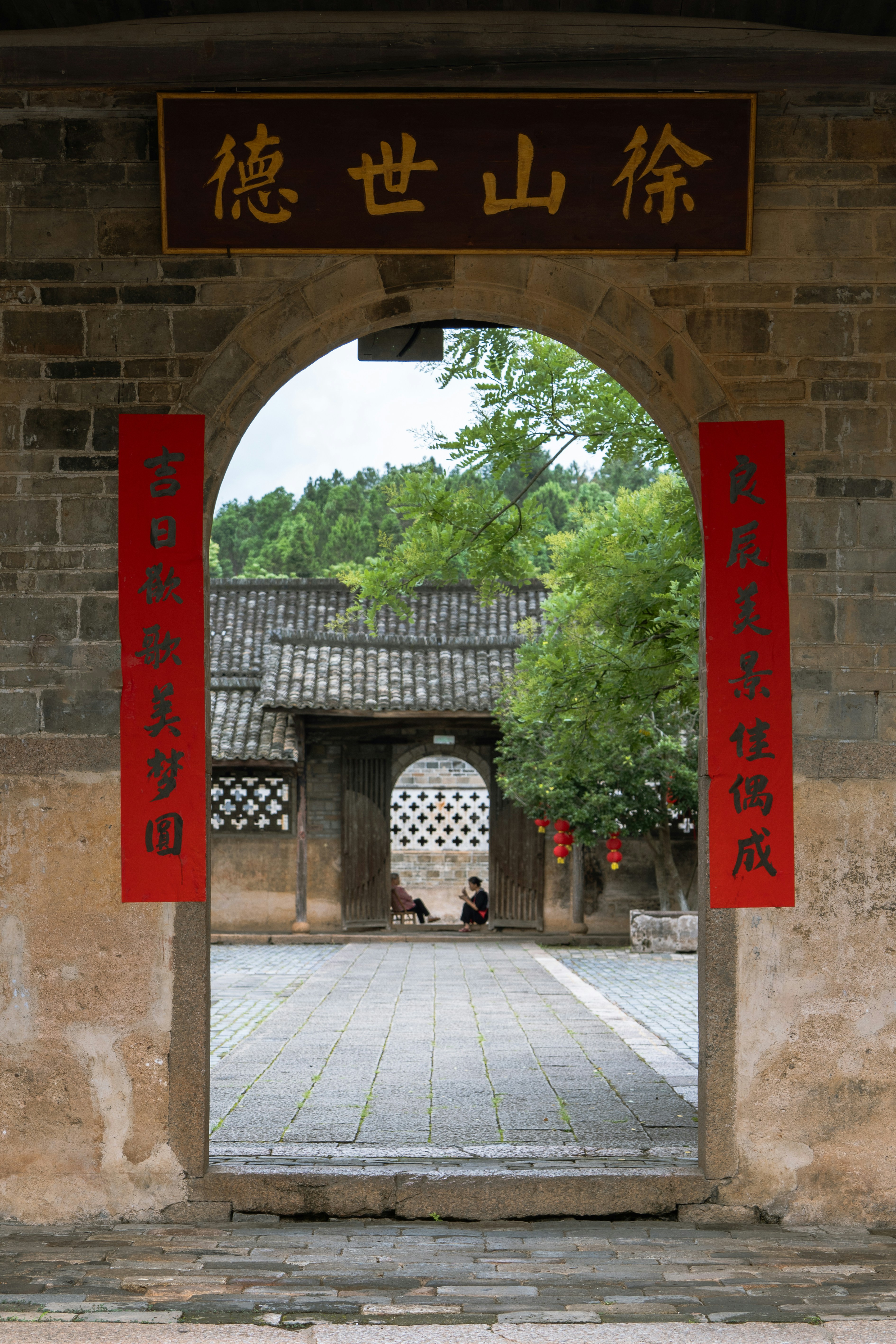 Stone archway frames an ancient chinese courtyard.