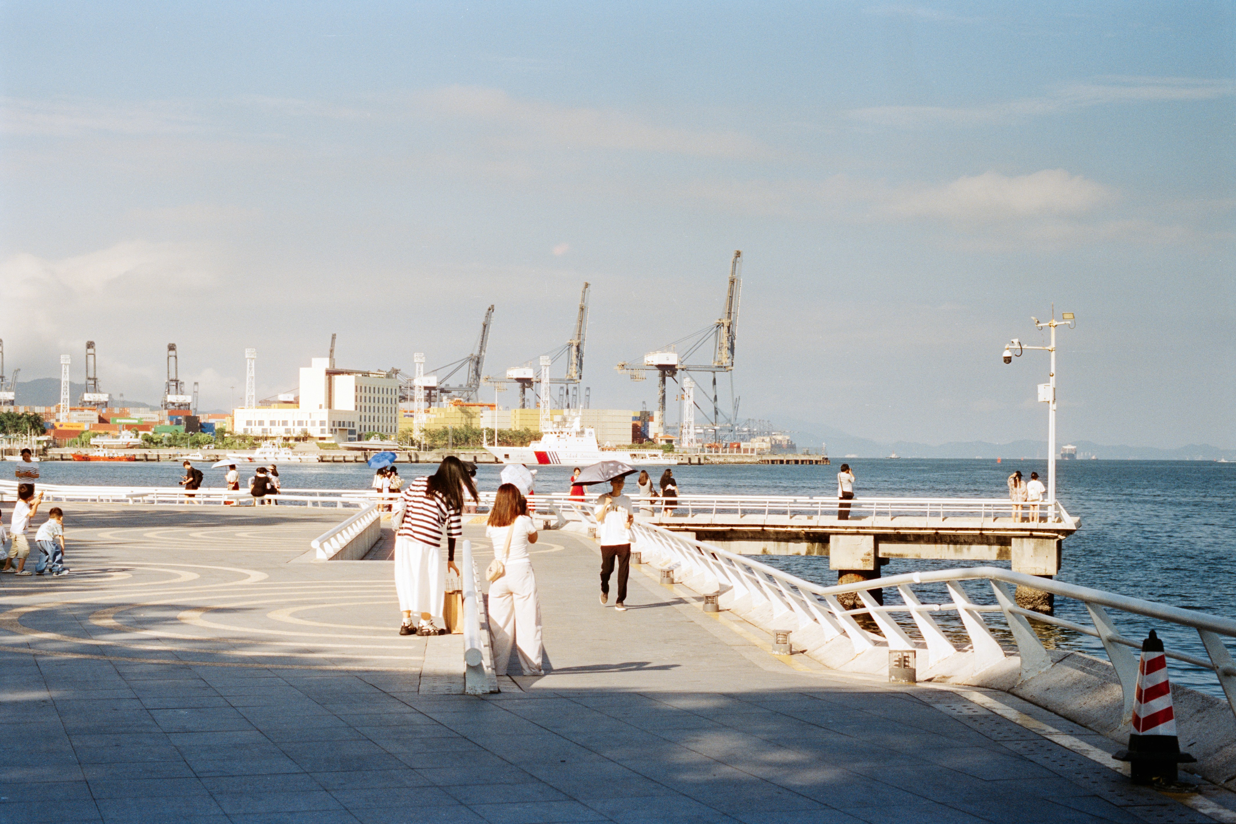 People walk on a pier near a sunny coastline. photo – Free Street ...