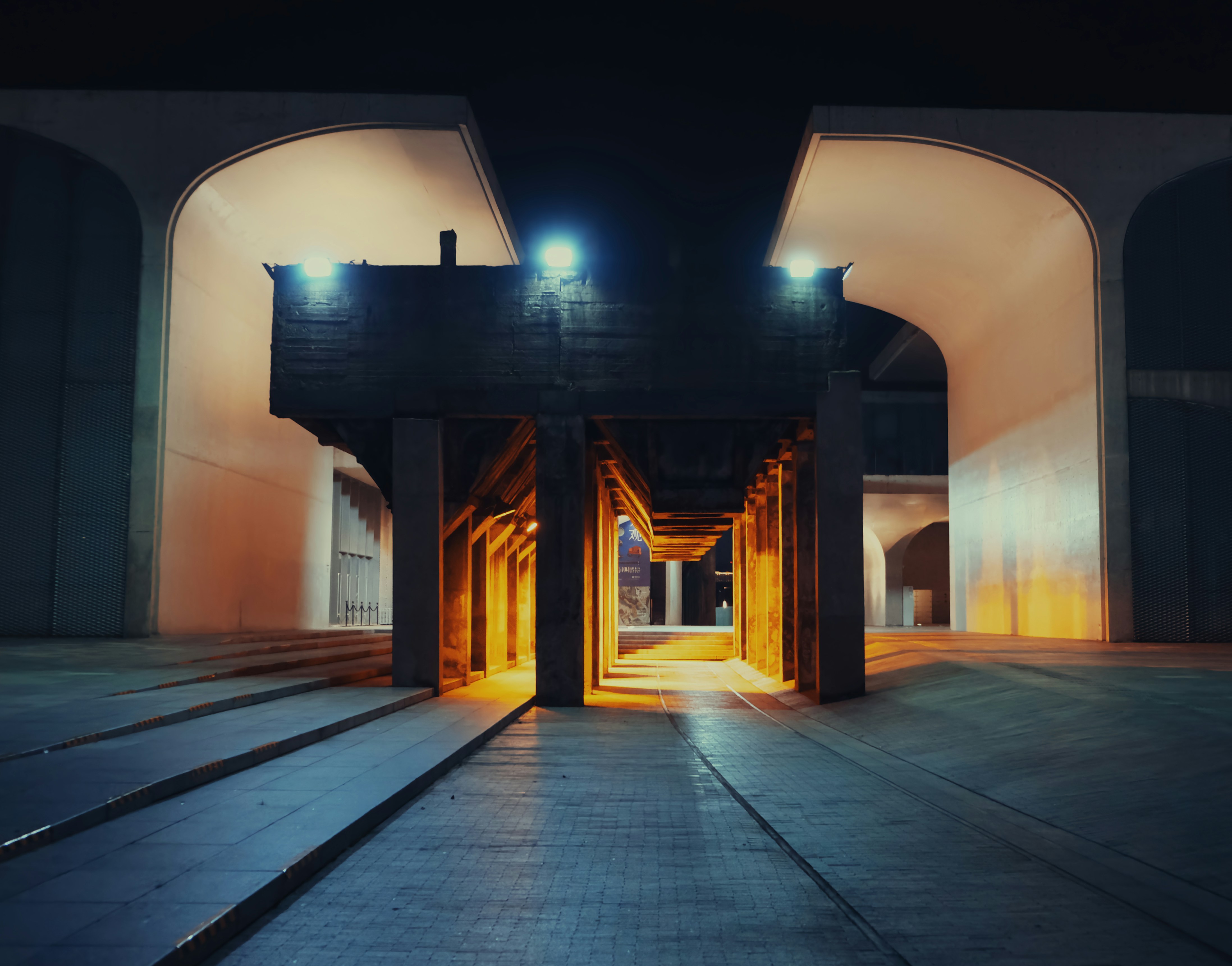 Dramatic interplay of light and shadow in a modern architectural space at night, showcasing geometric forms and illuminated pathways.