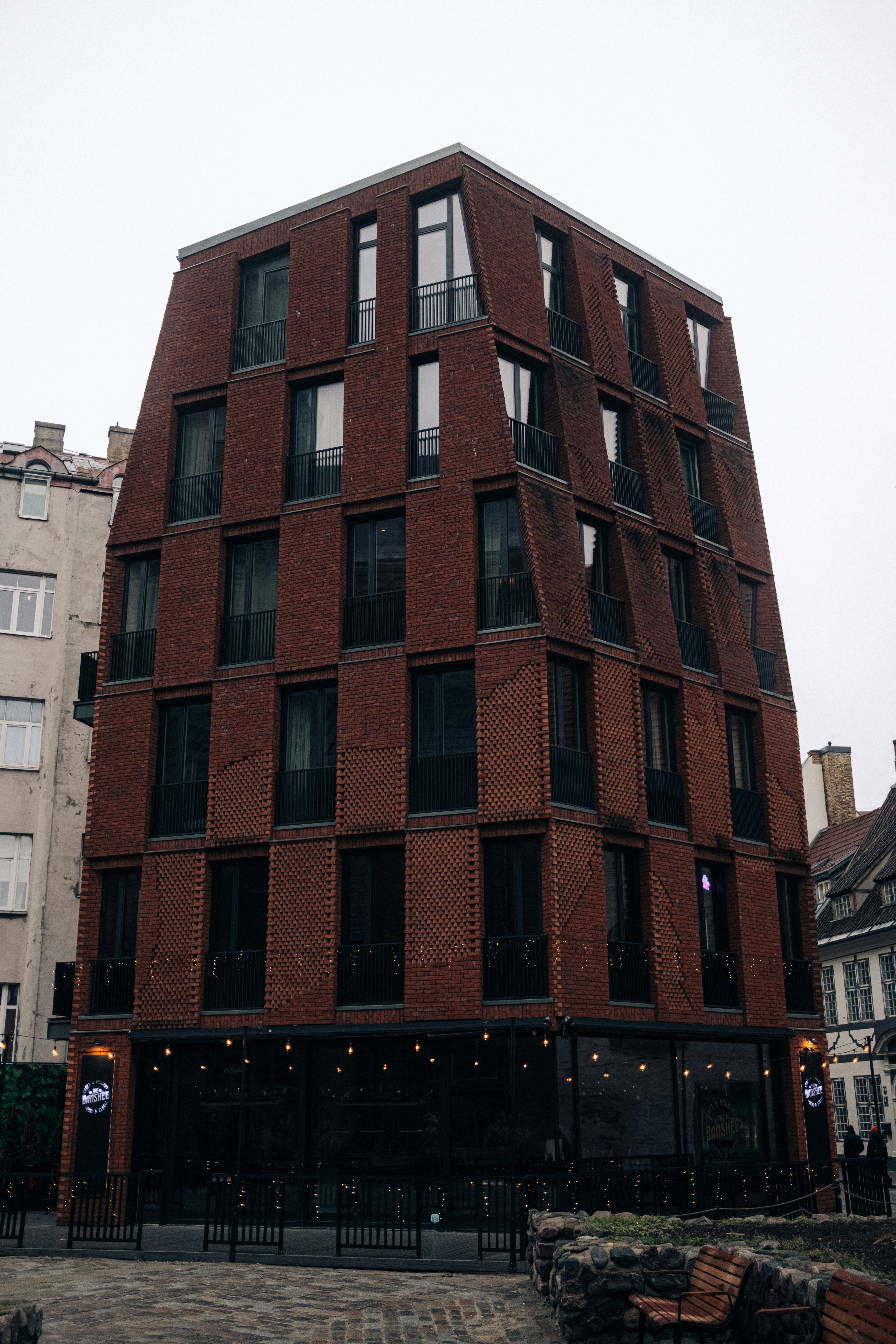 Brick Facade Tower Beneath a Pale Sky with Lantern Glow