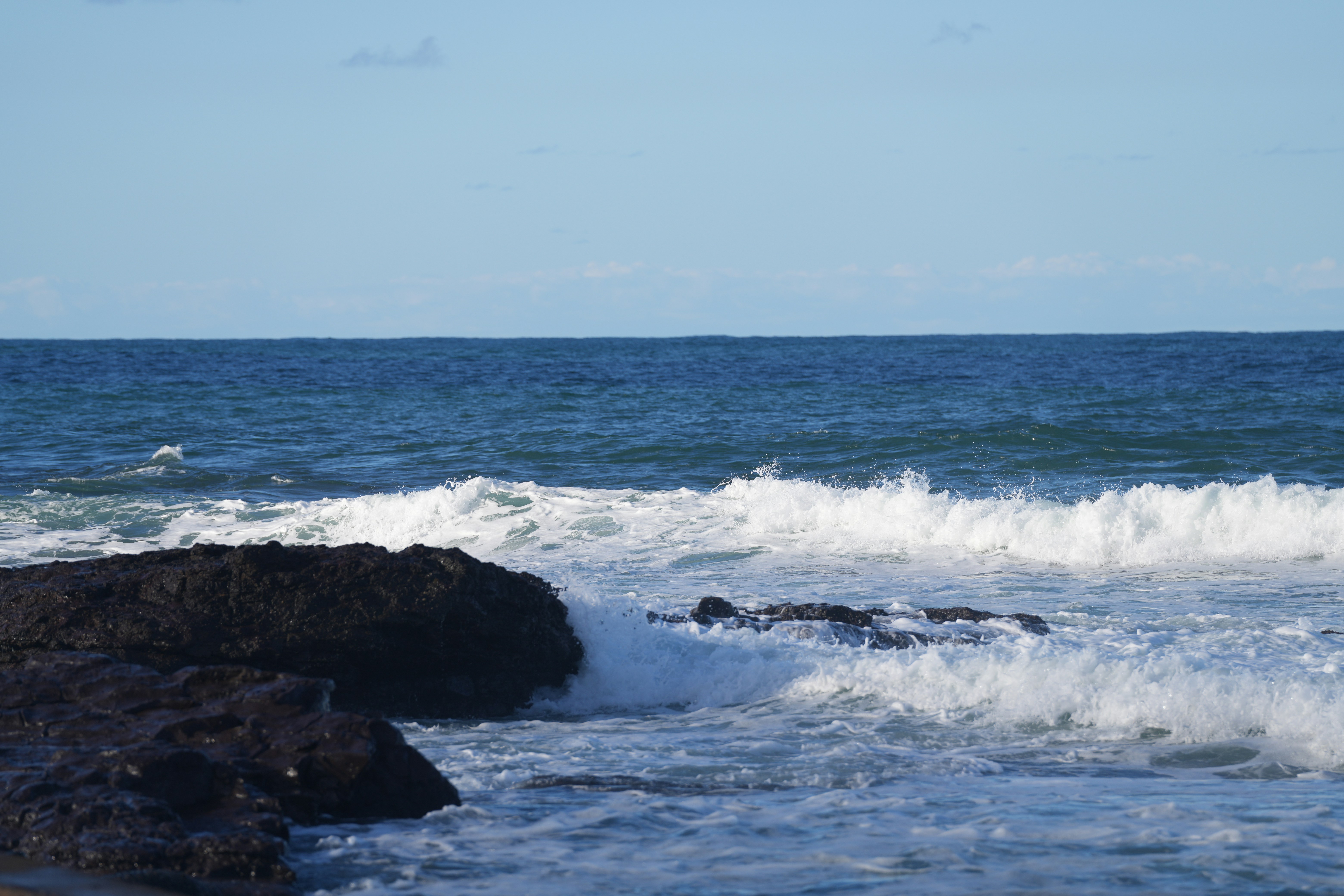 Waves crash against rocks at the ocean.