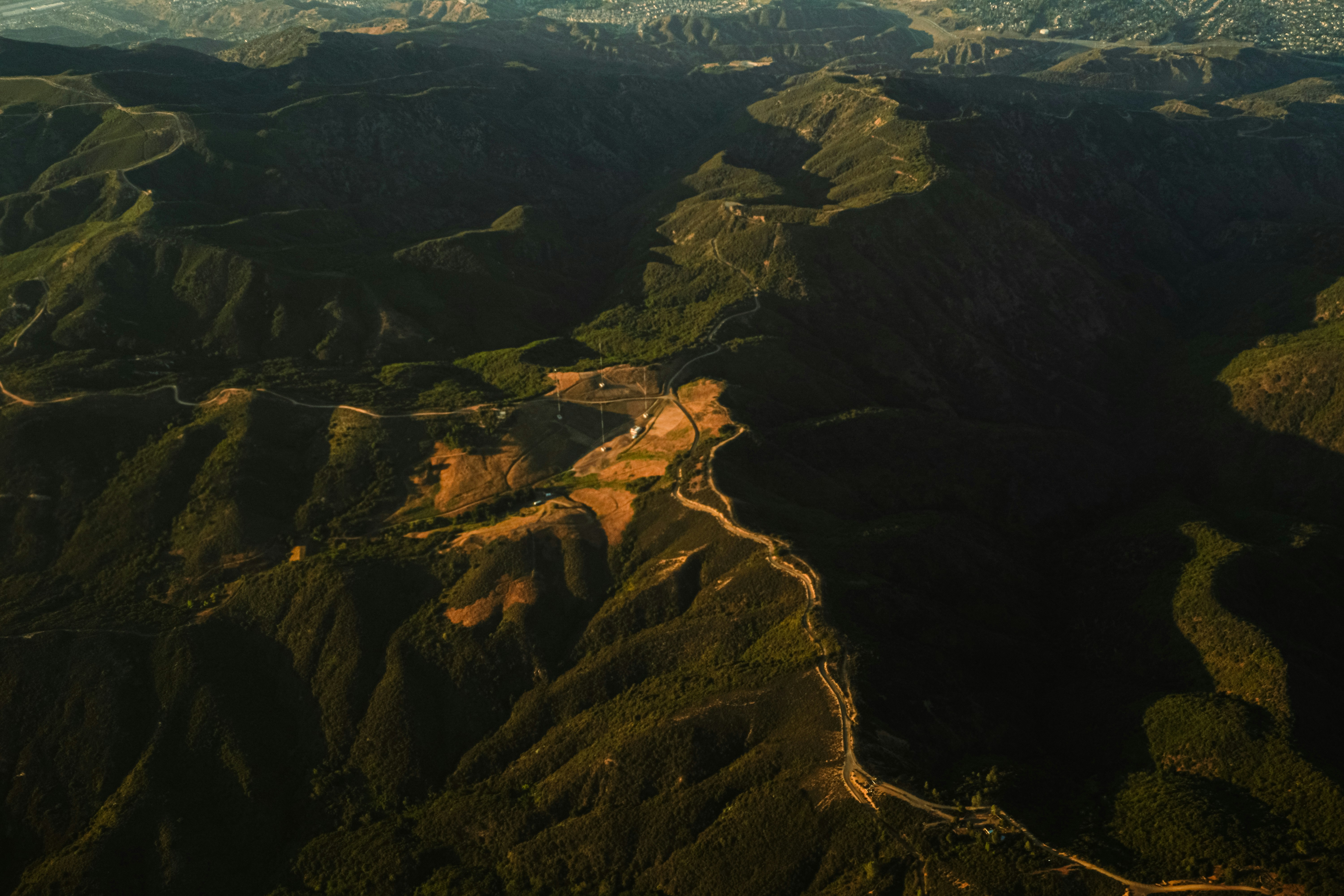 An aerial shot during an airplane descent into SNA | Mountains and valleys are seen from an aerial view.