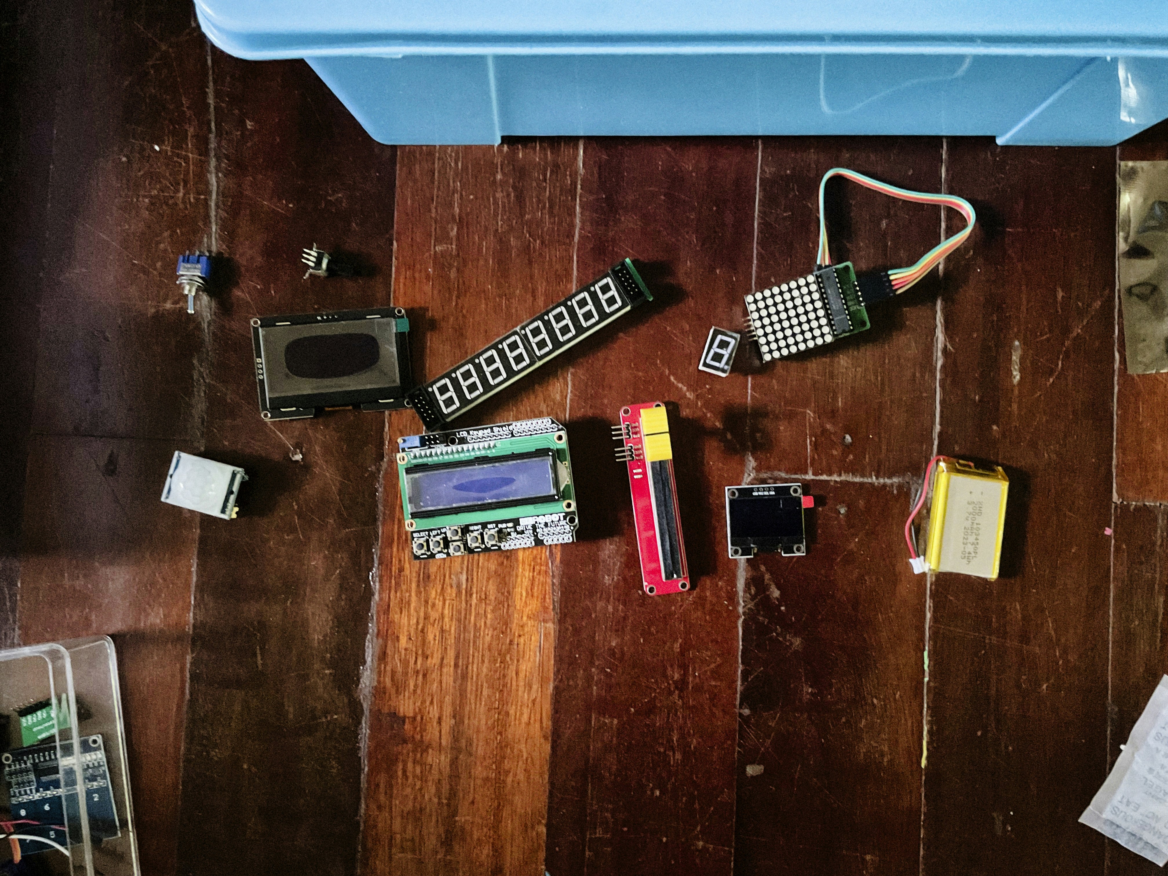 Assorted electronic components scattered on a wooden surface, showcasing a blend of technology and creativity.