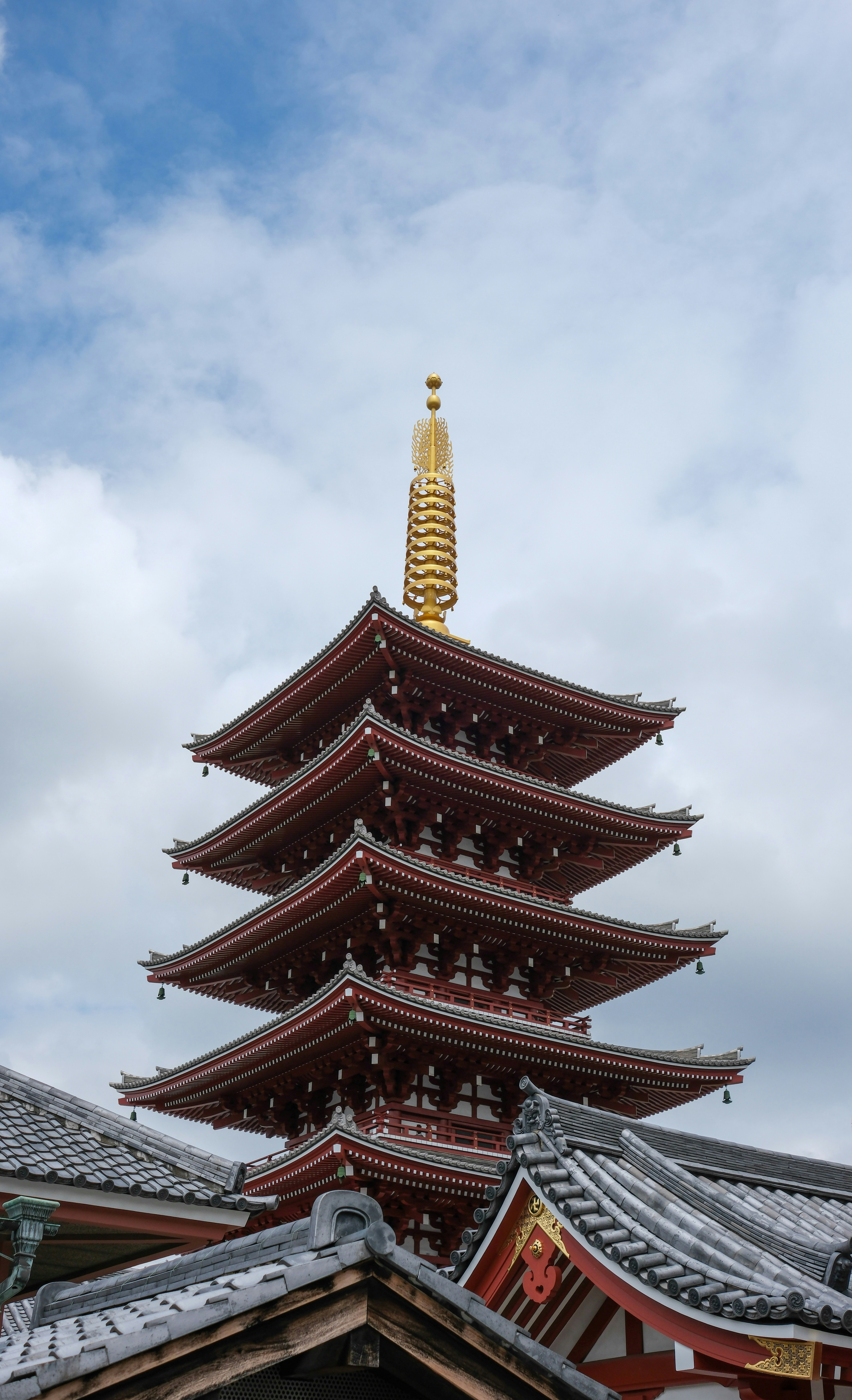 Five-story pagoda adorned with intricate details, rising against a backdrop of cloudy skies. The golden spire adds a touch of elegance.