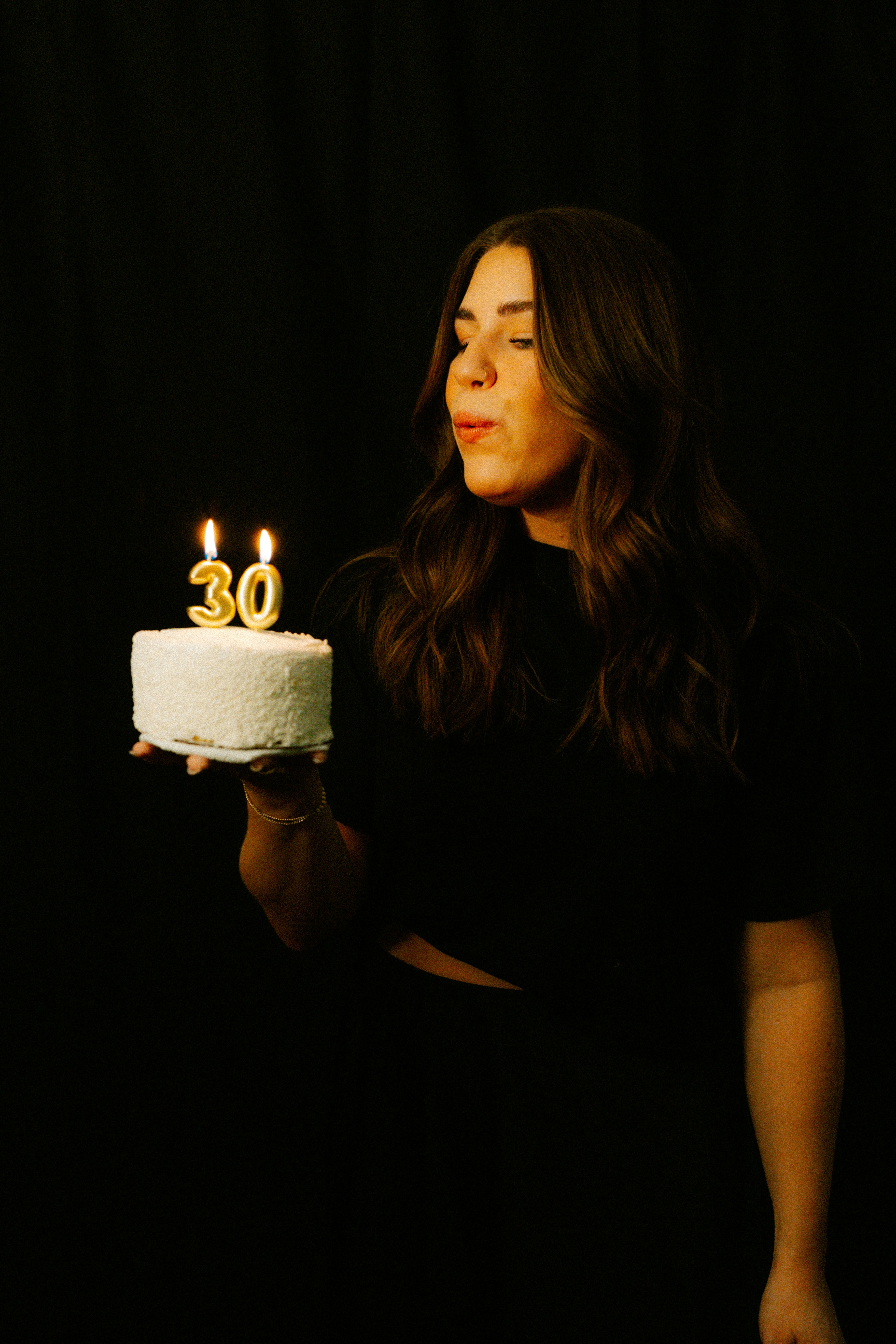 Woman blowing out candles on her birthday cake.