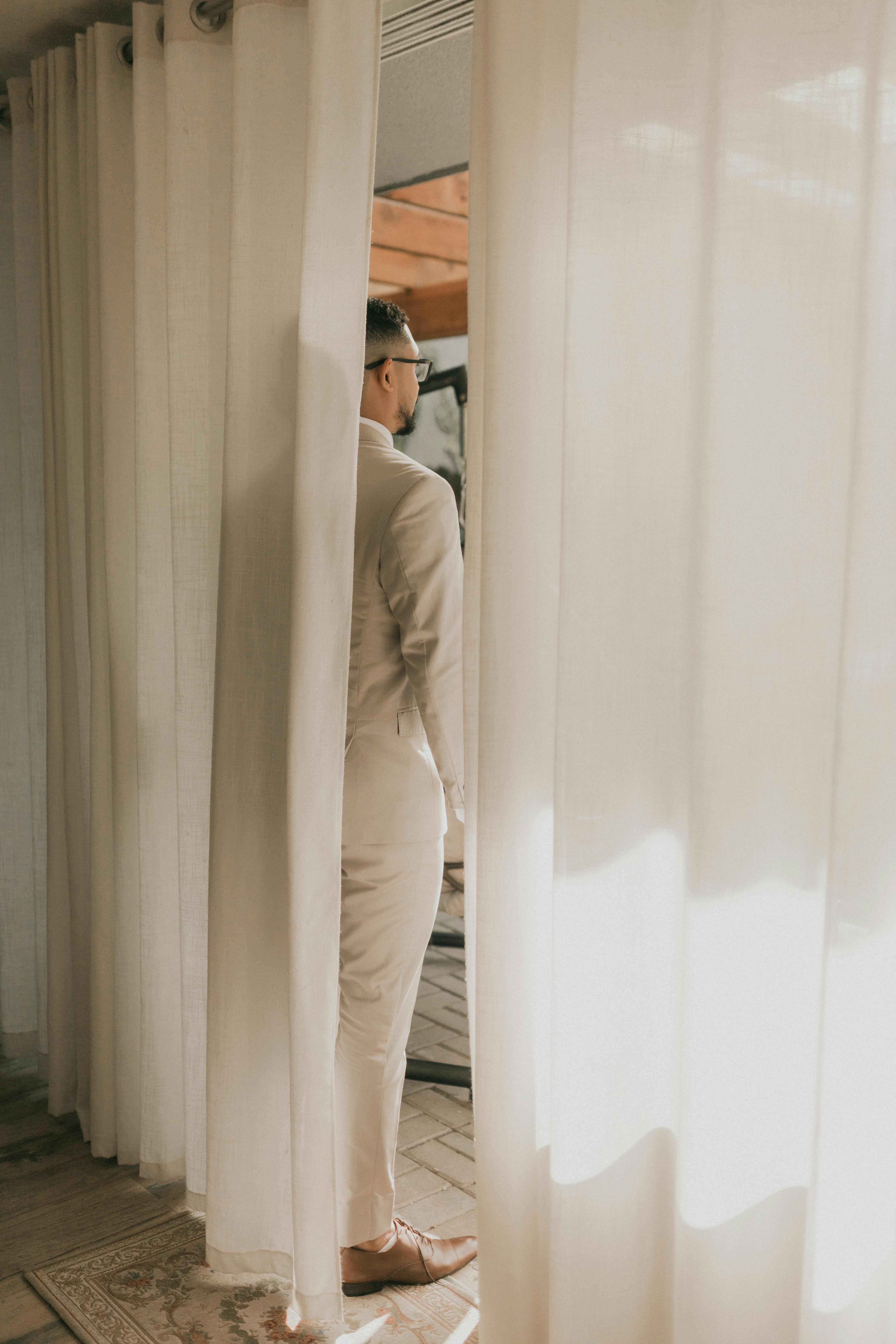 A man stands behind curtains, looking ahead.