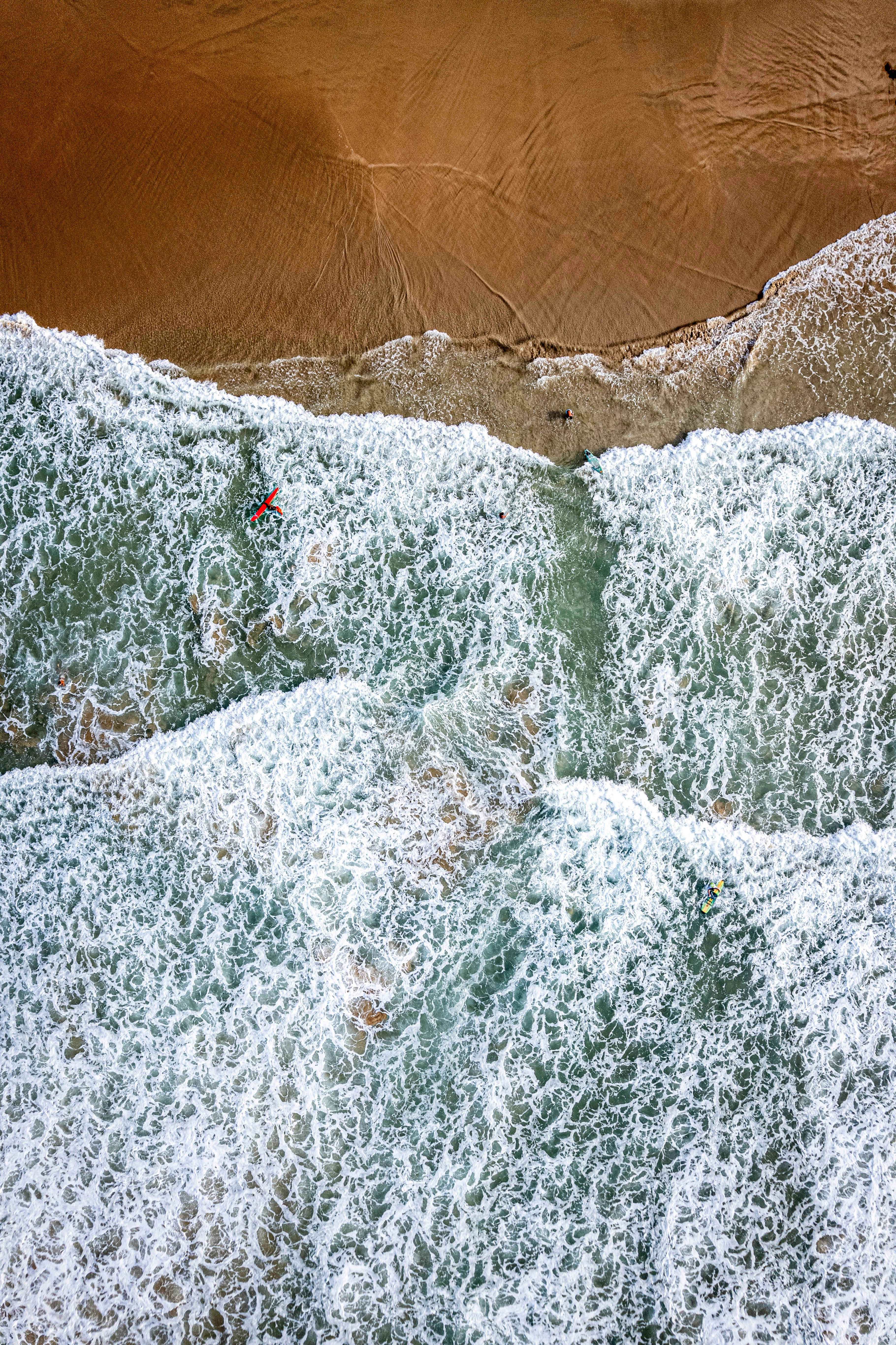 Curved Crest: Aerial Dance of Sea Foam Along Bronzed Shore