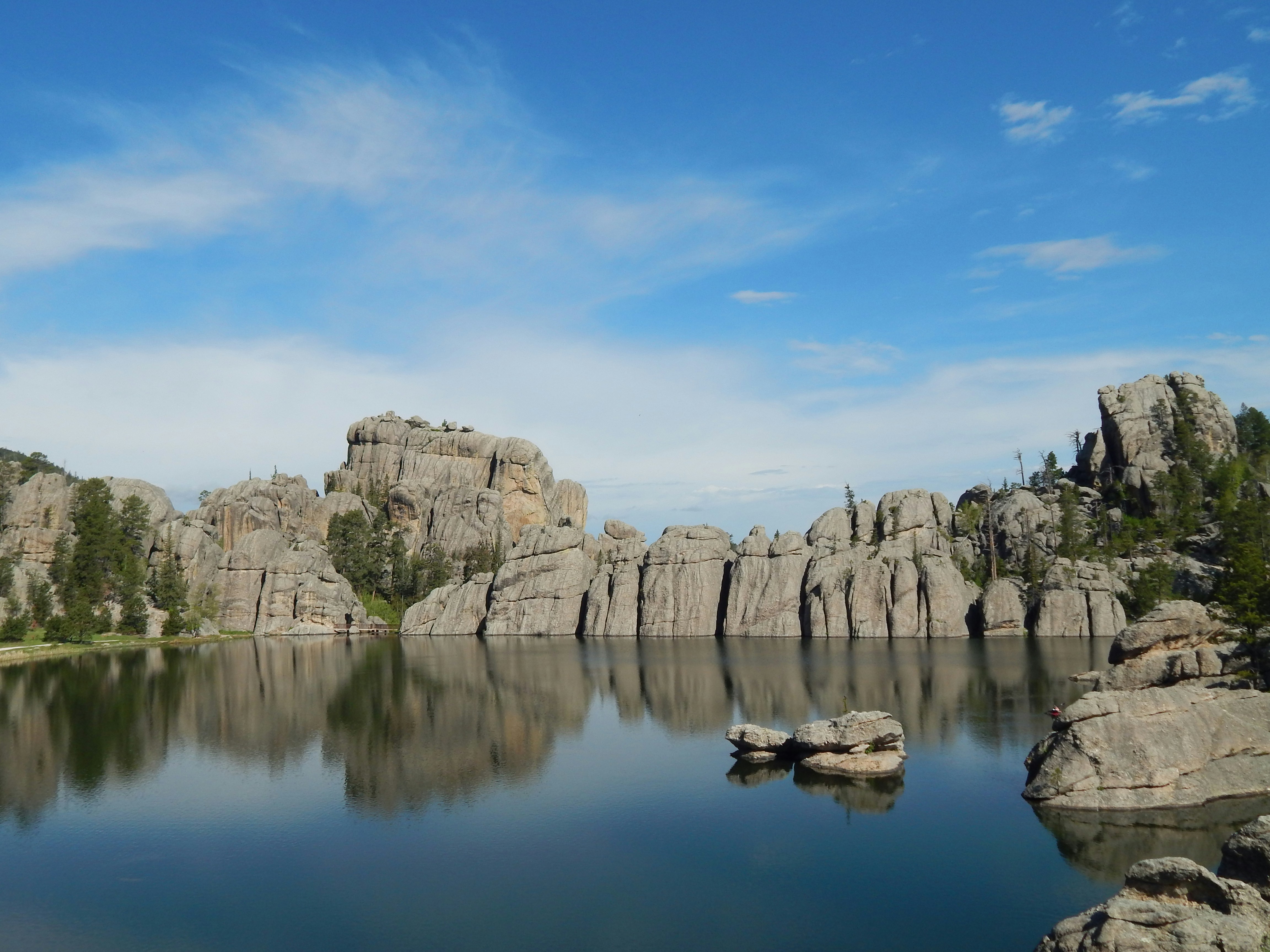 Rocky cliffs reflect in a calm lake.