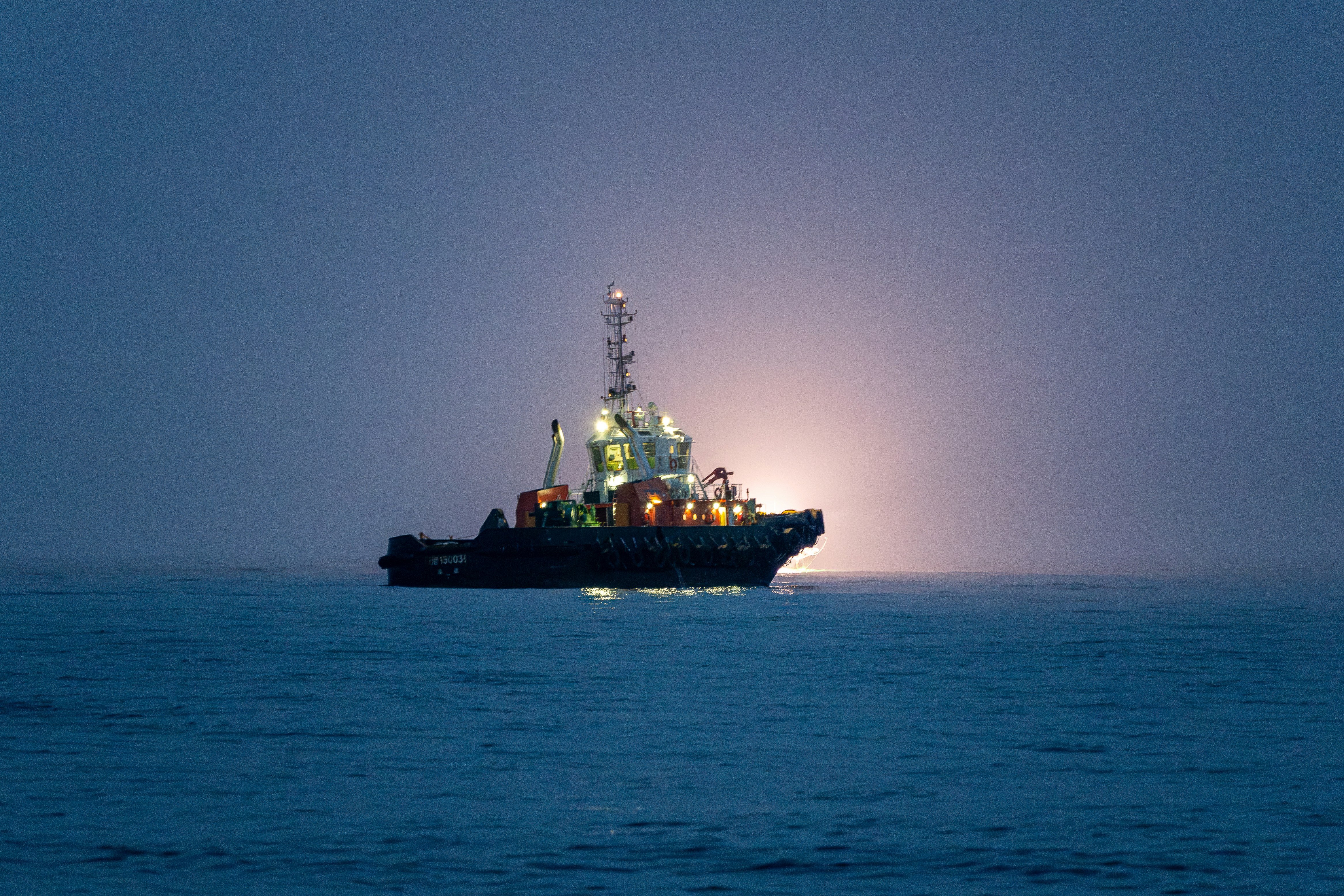 Backlit Horizon Tug: A Quiet Beacon Over Midnight Blue Waters