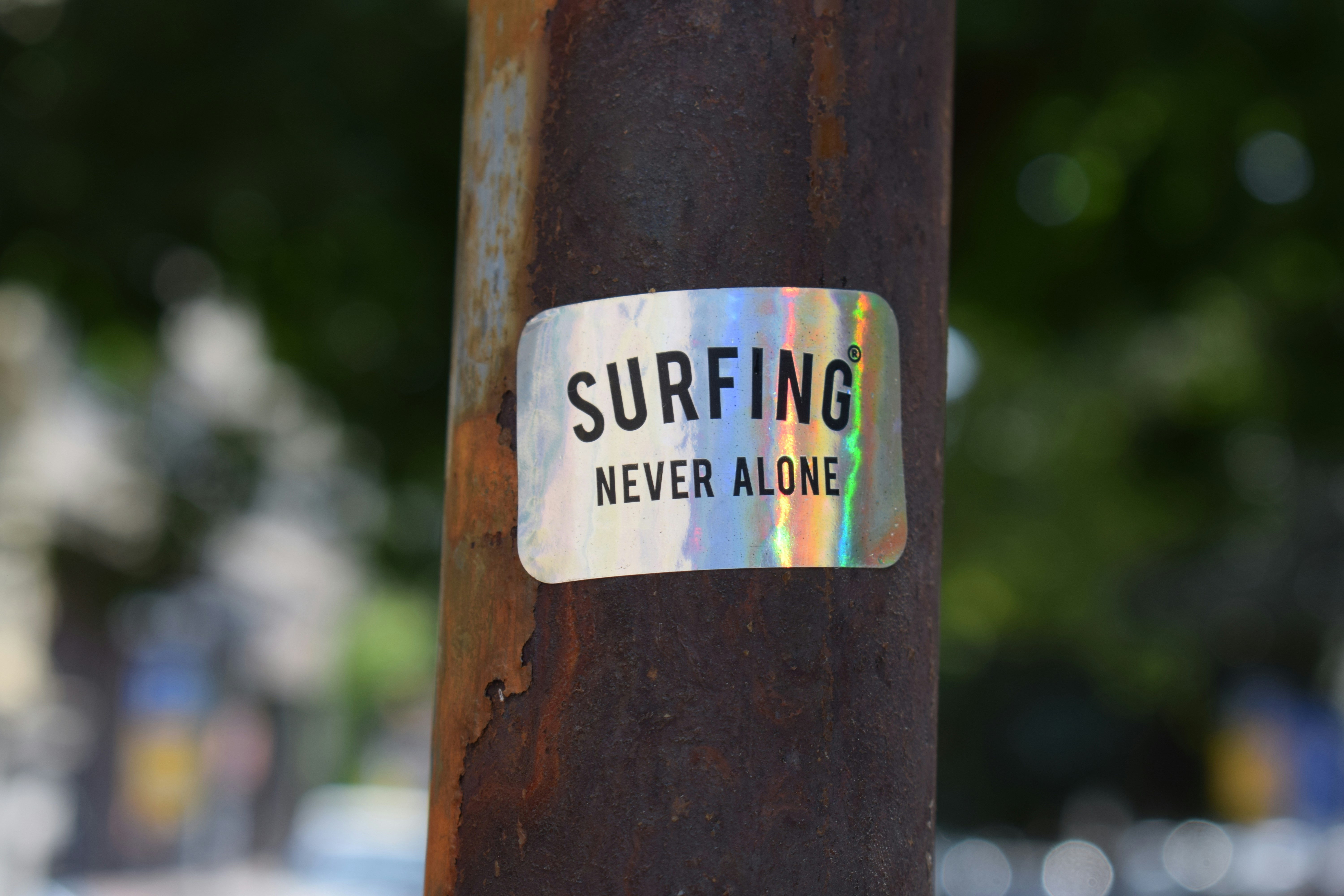A surfing sticker is placed on a rusty pole. photo – Free Sticker Image ...