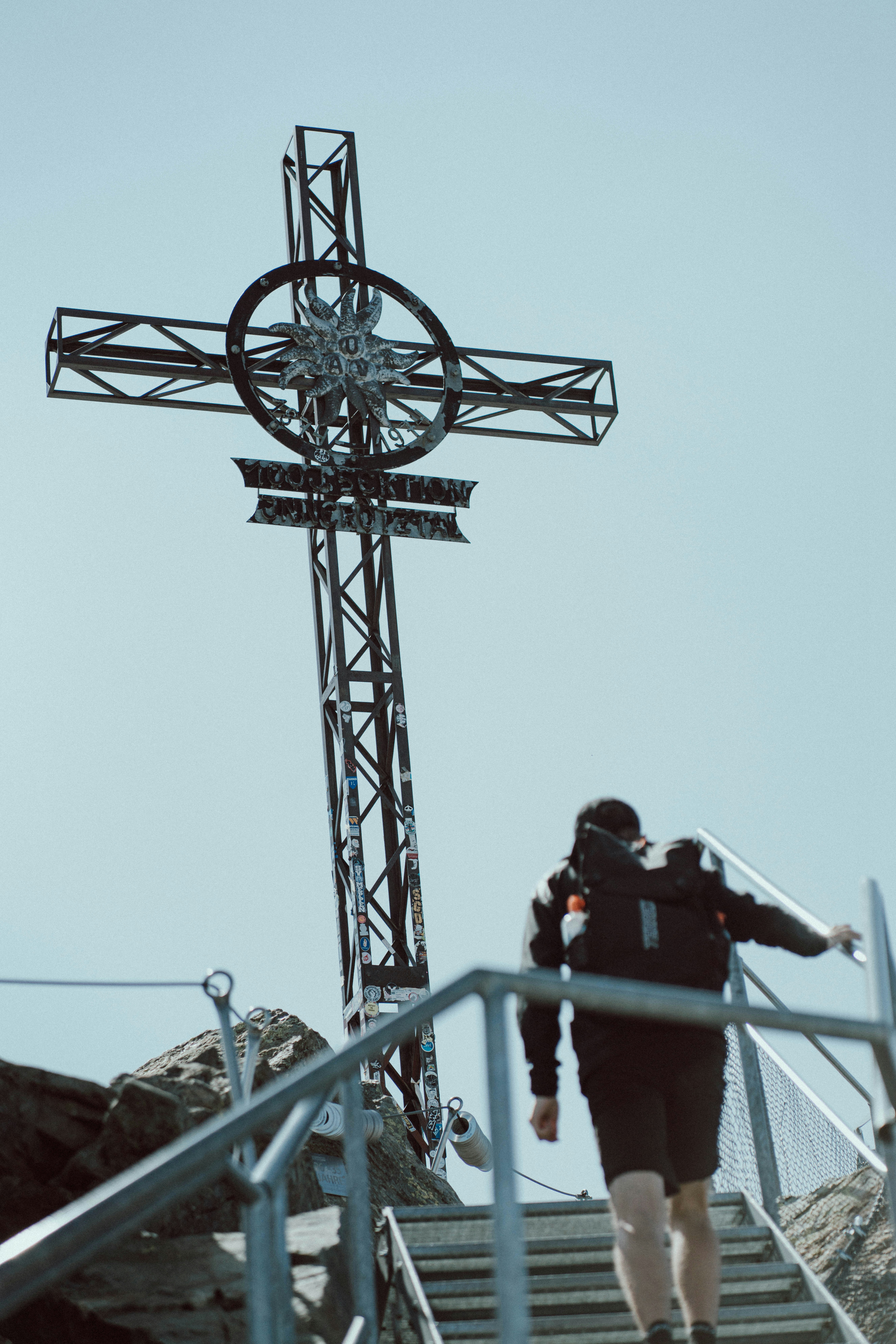 A hiker ascends towards the summit cross.