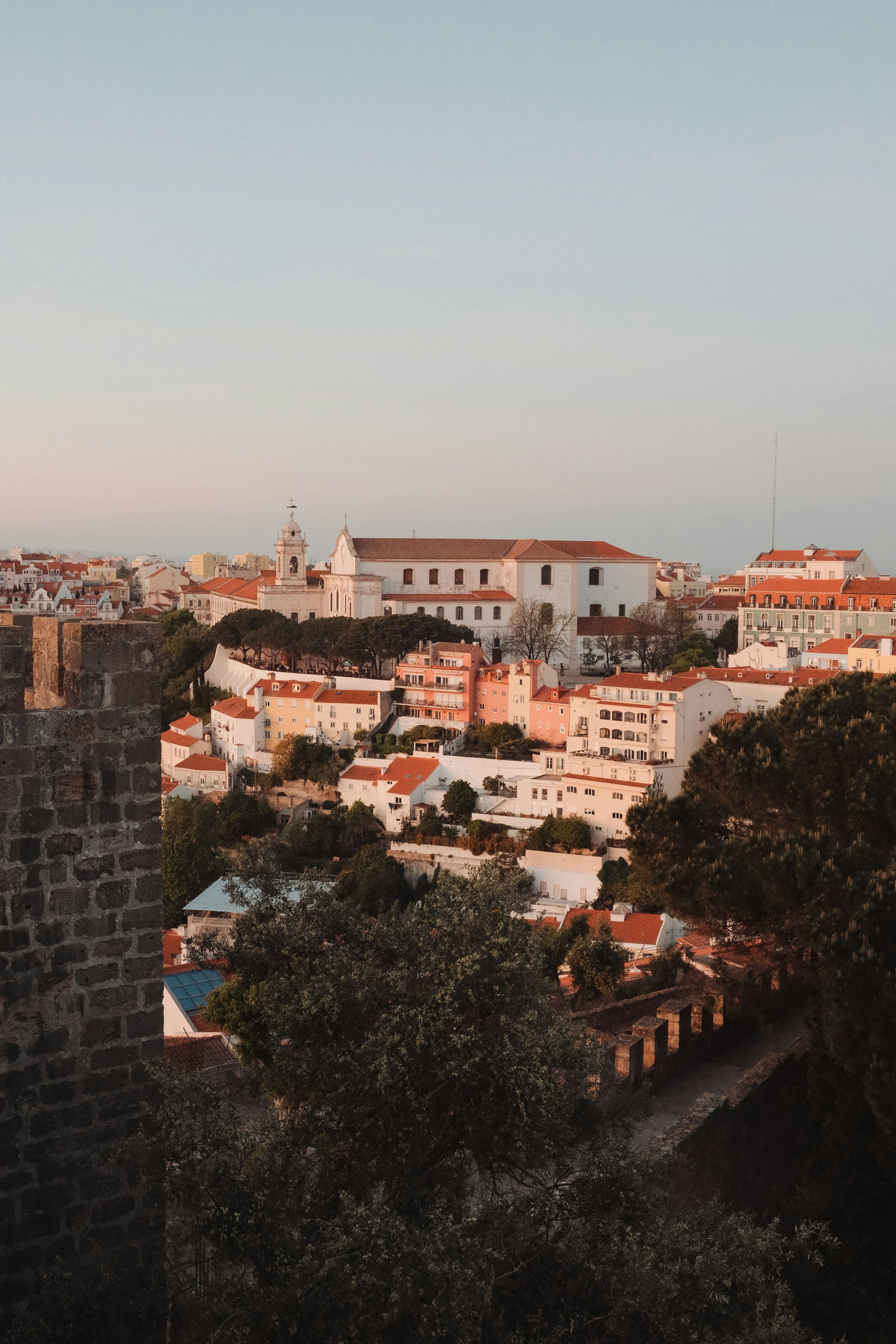 Historic architecture and terracotta rooftops blend seamlessly in a tranquil evening scene. The fading light casts a warm glow over the cityscape.