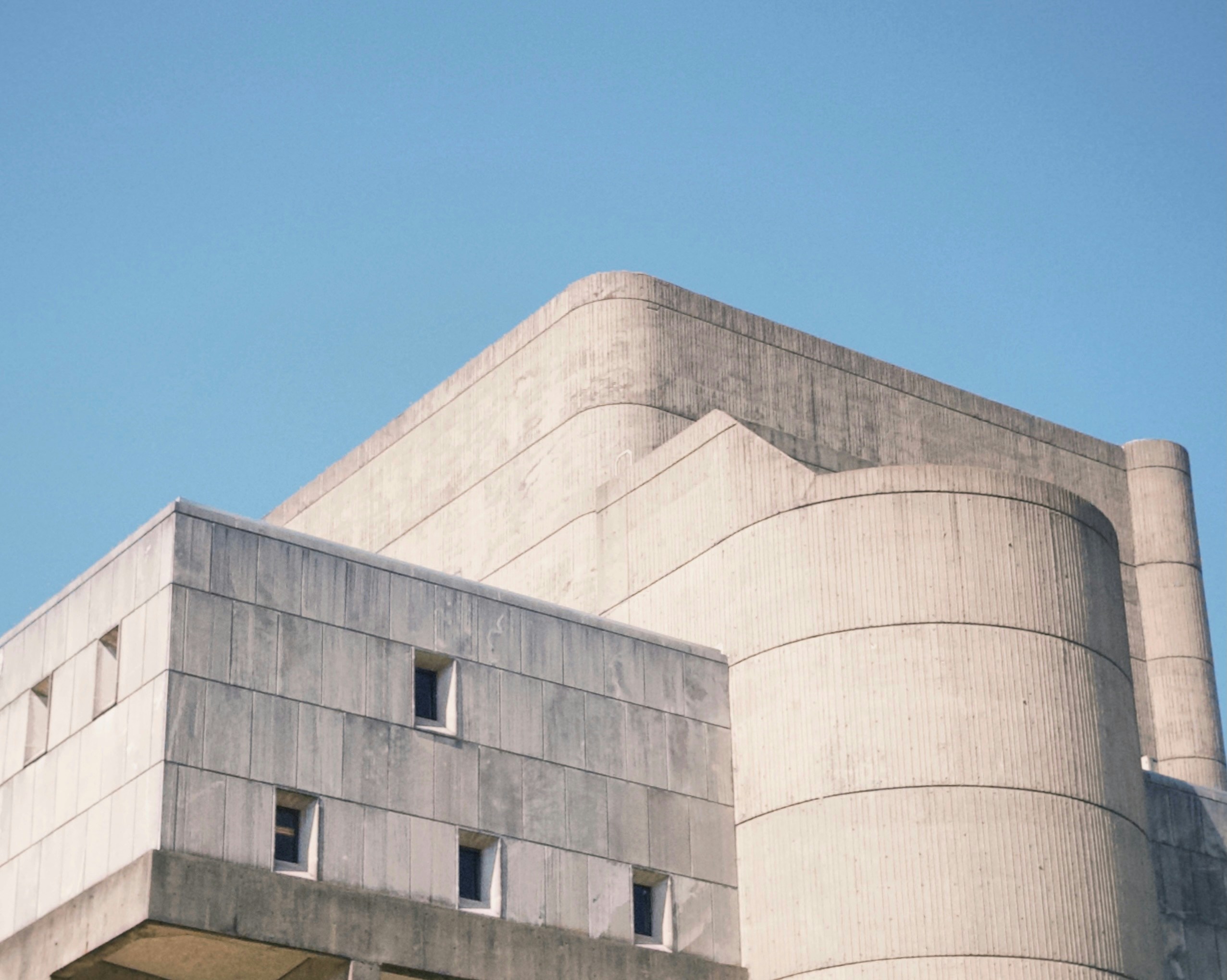 Abstract architectural details of a modern concrete structure against a clear blue sky.