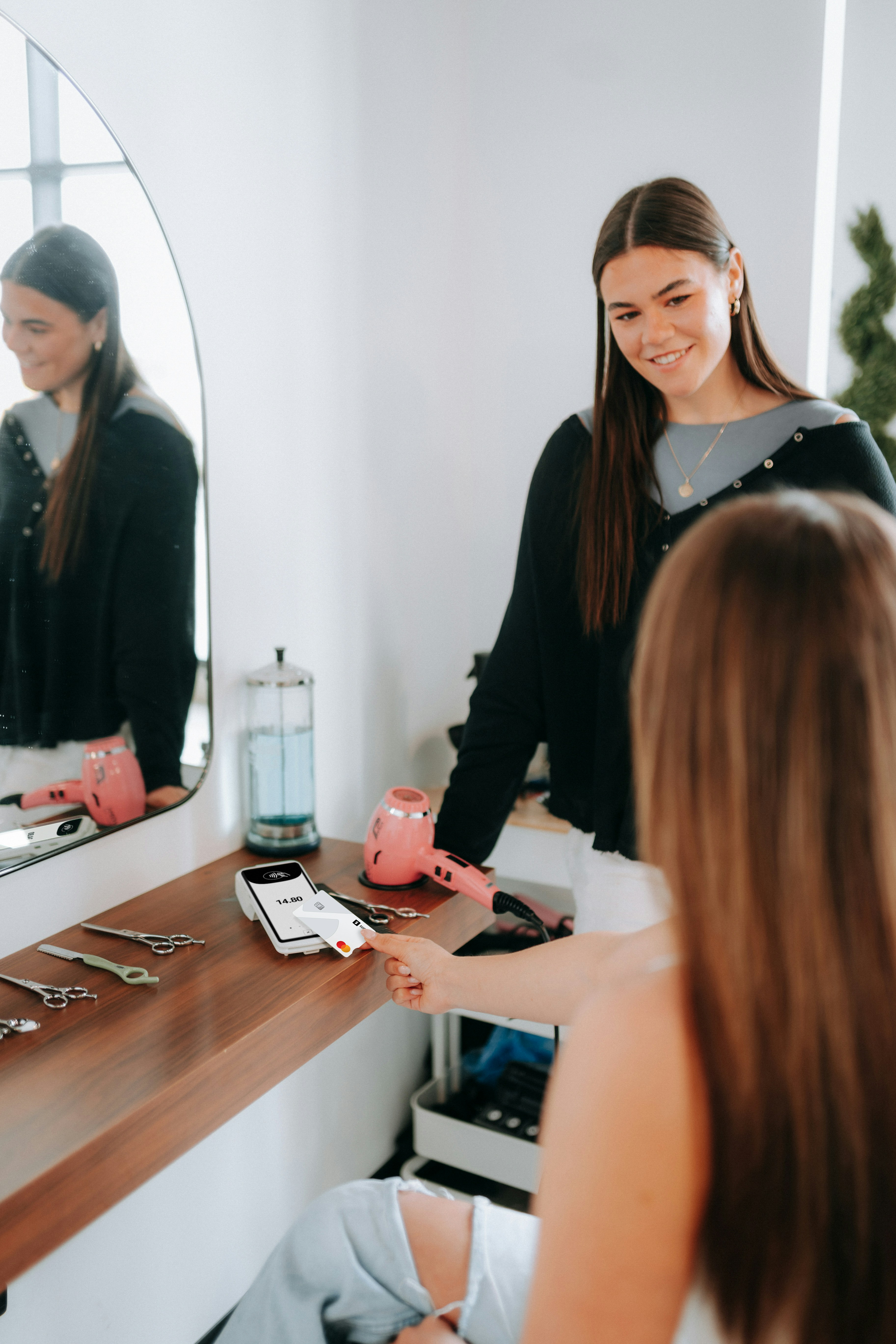 Sunlit beauty salon with a client in the chair and the SumUp device set up for payment.