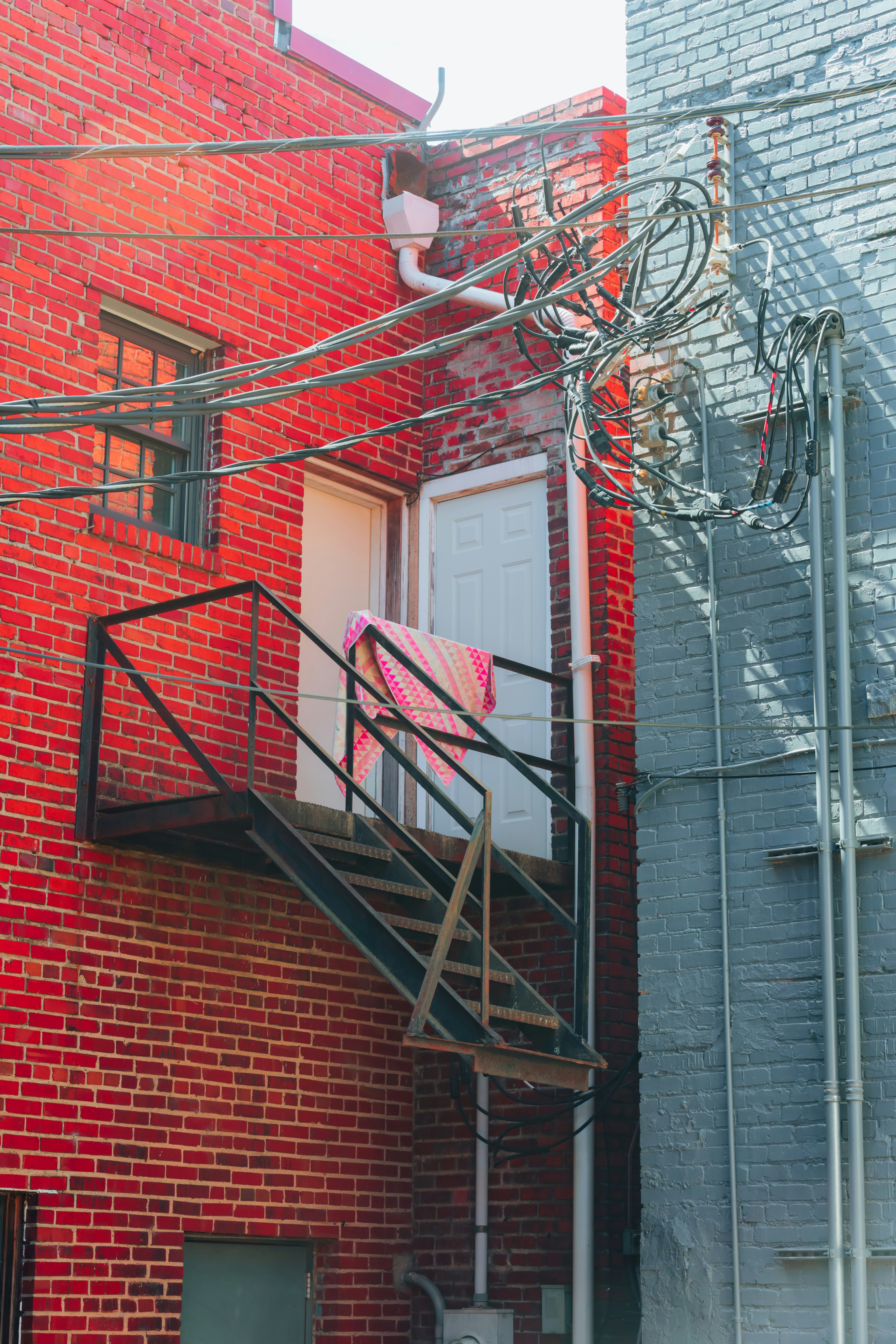Color Pop on a Fire Escape: Pink Towel Between Red and Gray Brick