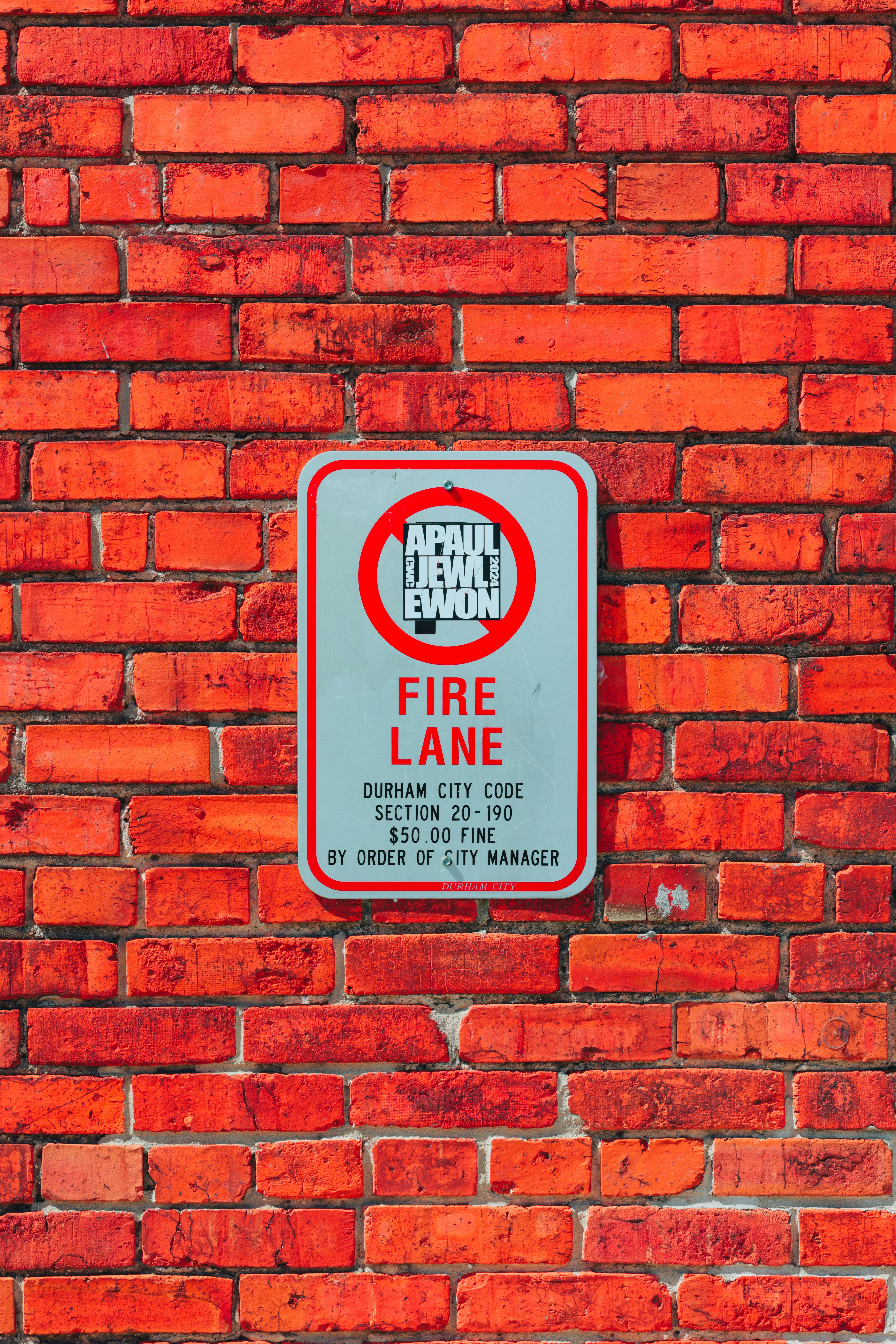 A fire lane sign is posted on a red brick wall. photo – Free ...