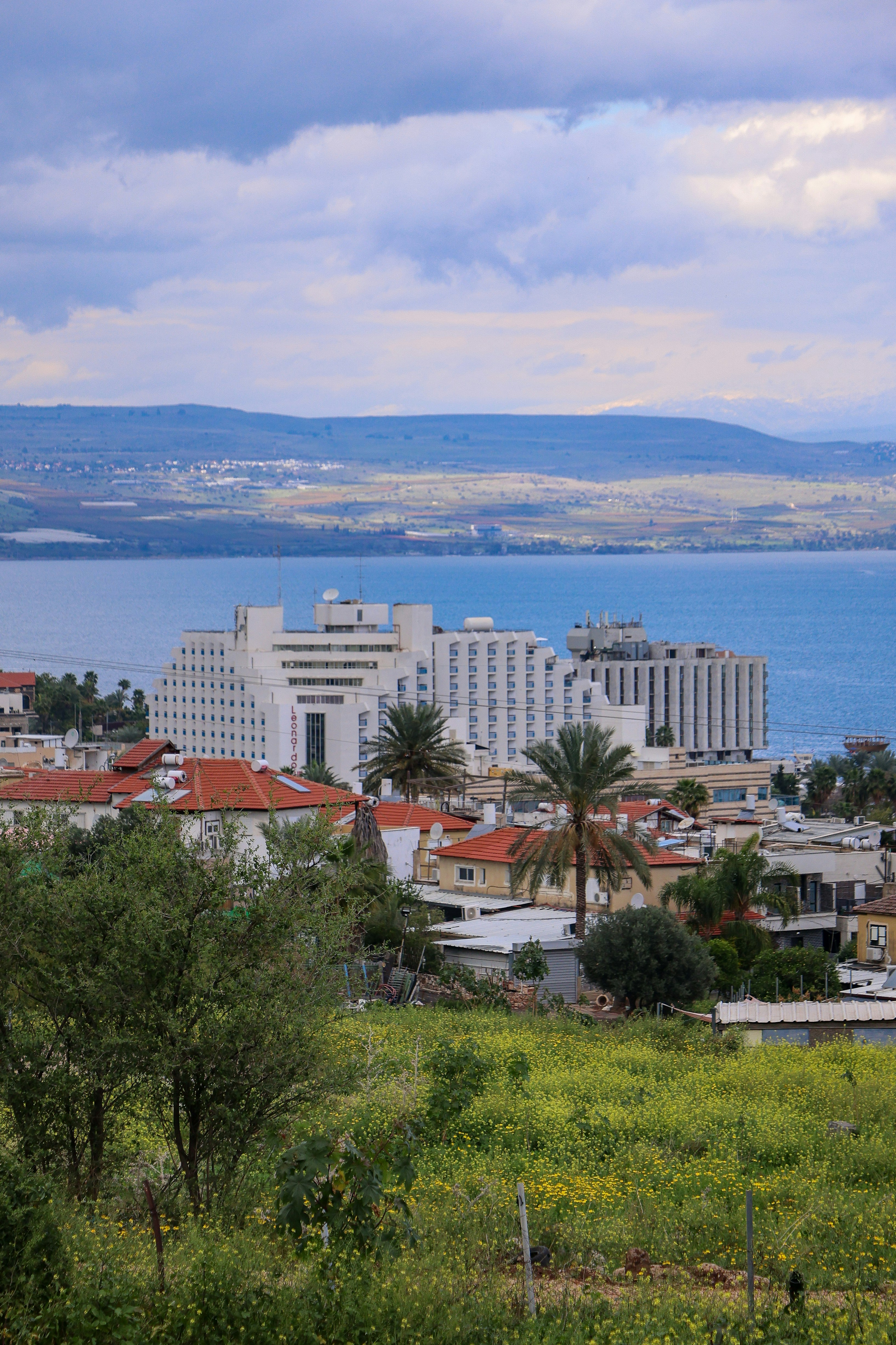 Modern hotel complex overlooking a tranquil lake, surrounded by lush greenery and distant hills. A perfect blend of nature and architecture.