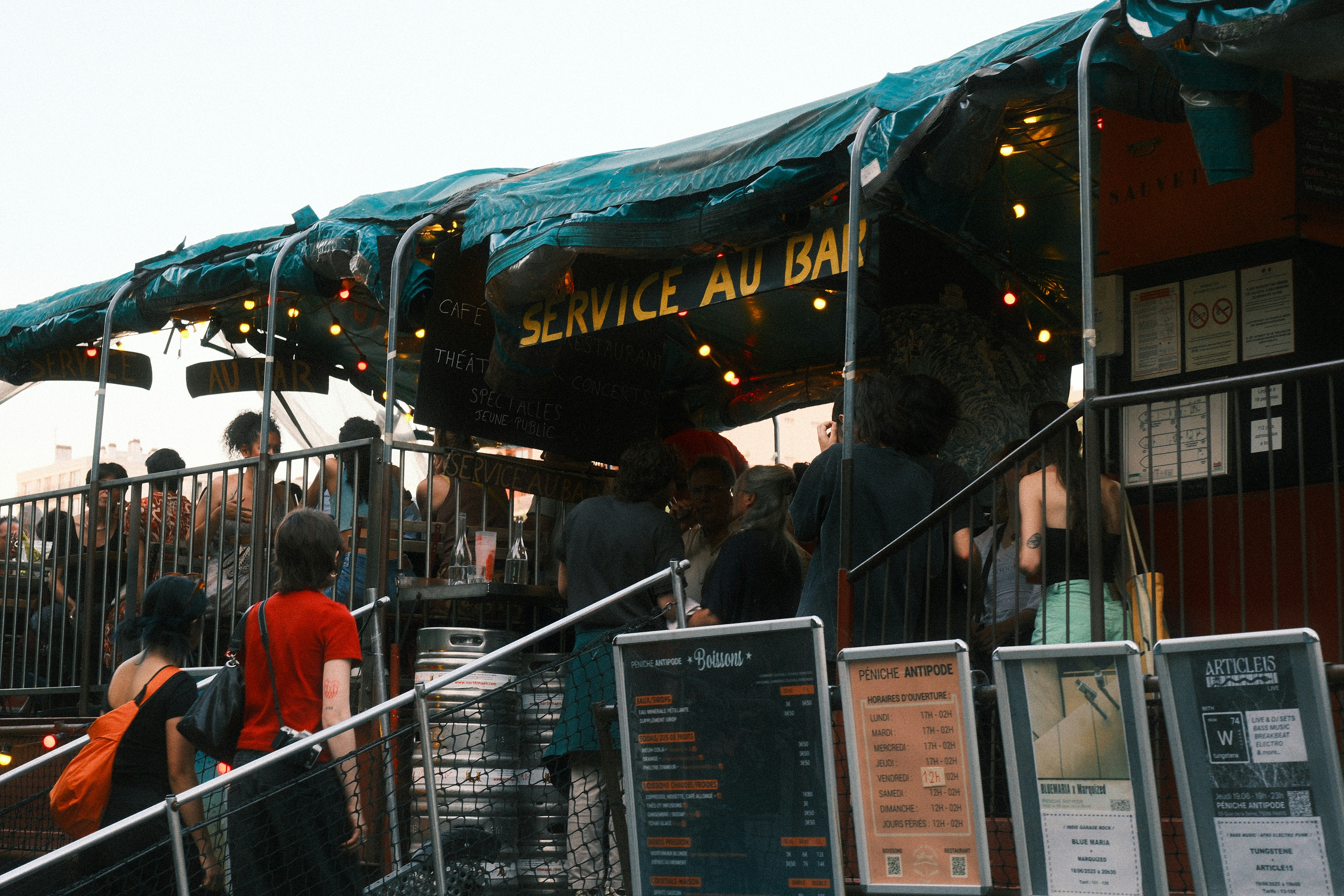 People queue at an outdoor bar with food menus. photo – Free People ...