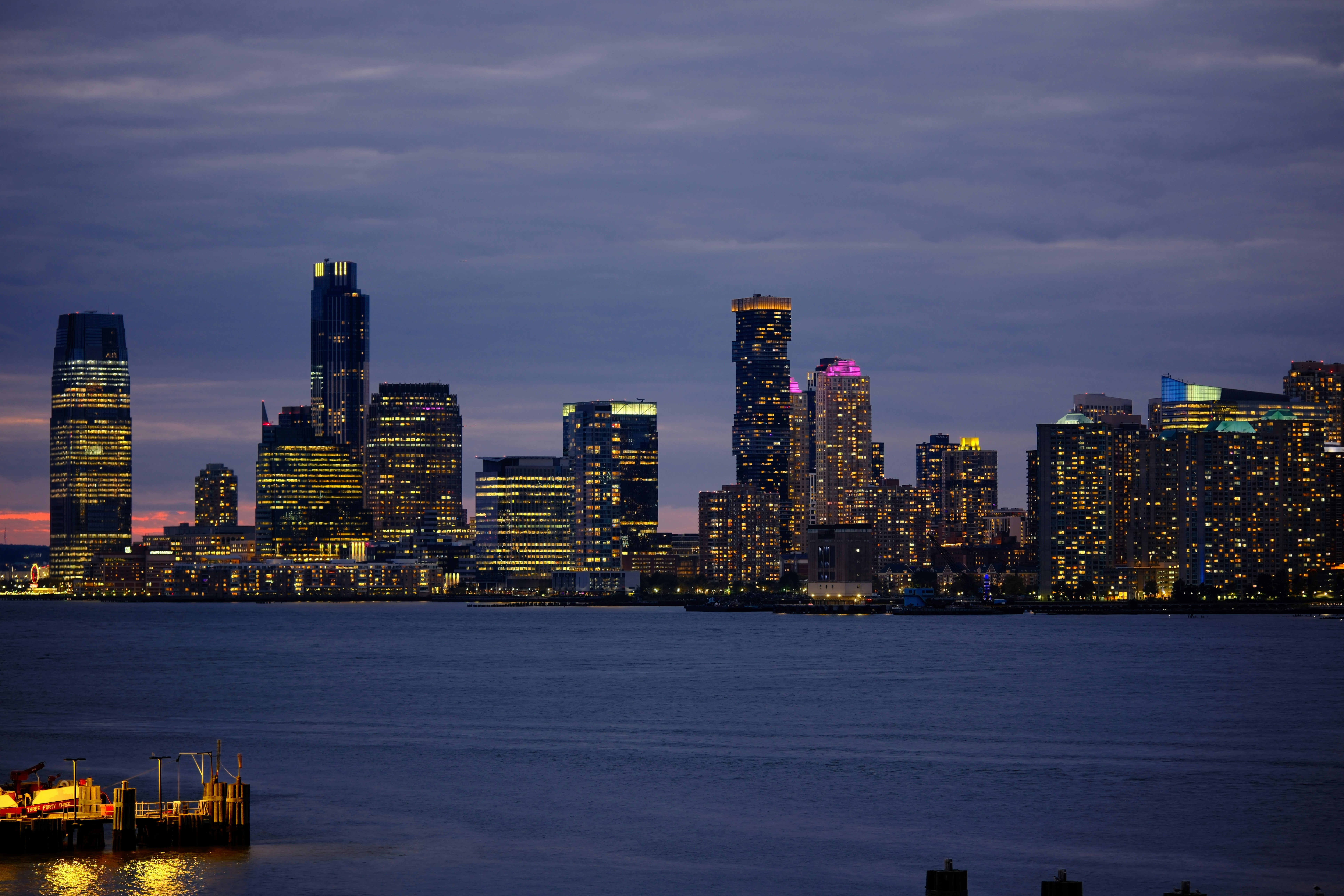 City skyline glows at dusk over water.