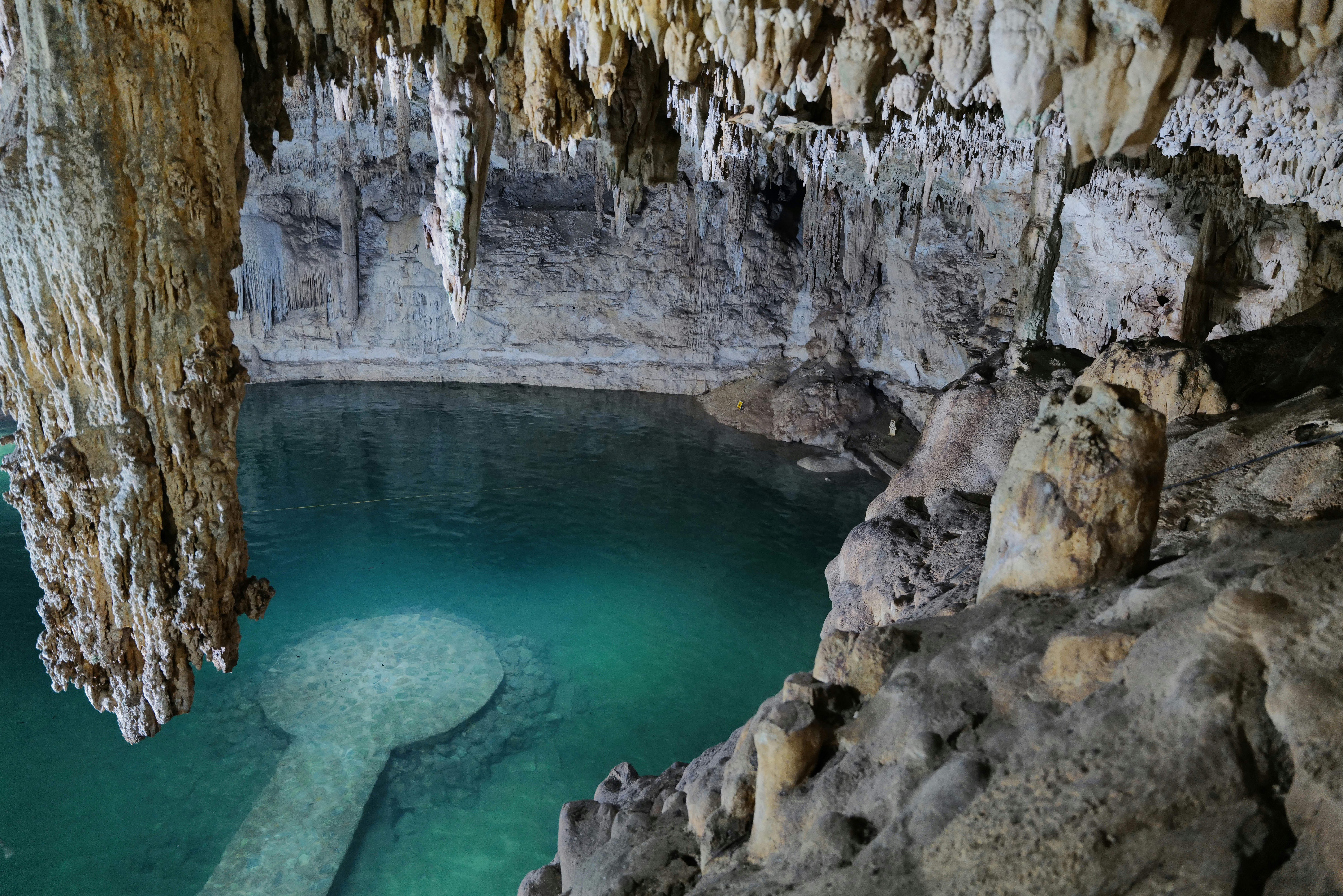 A cave with a turquoise pool of water.