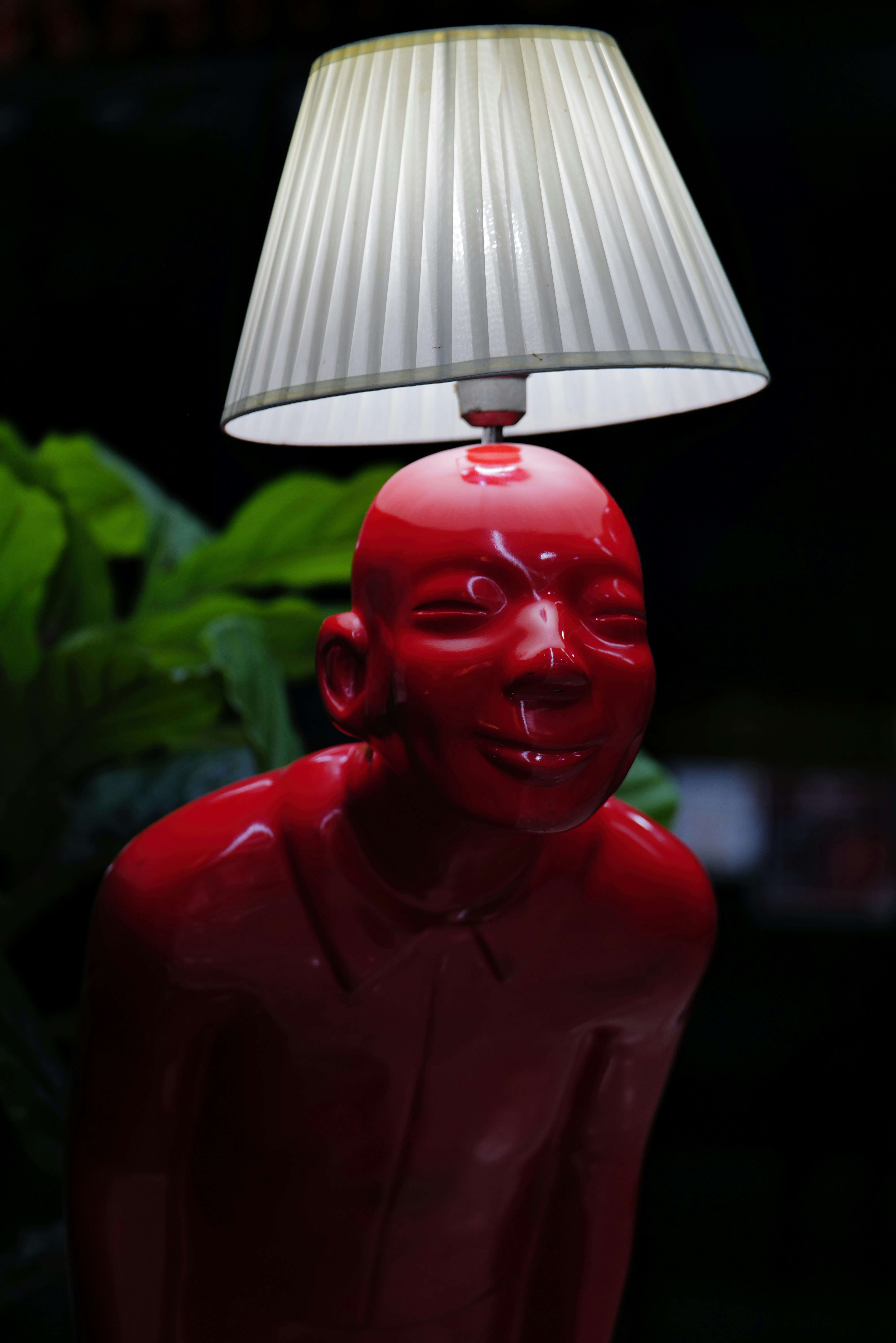 A red man statue with a lamp.