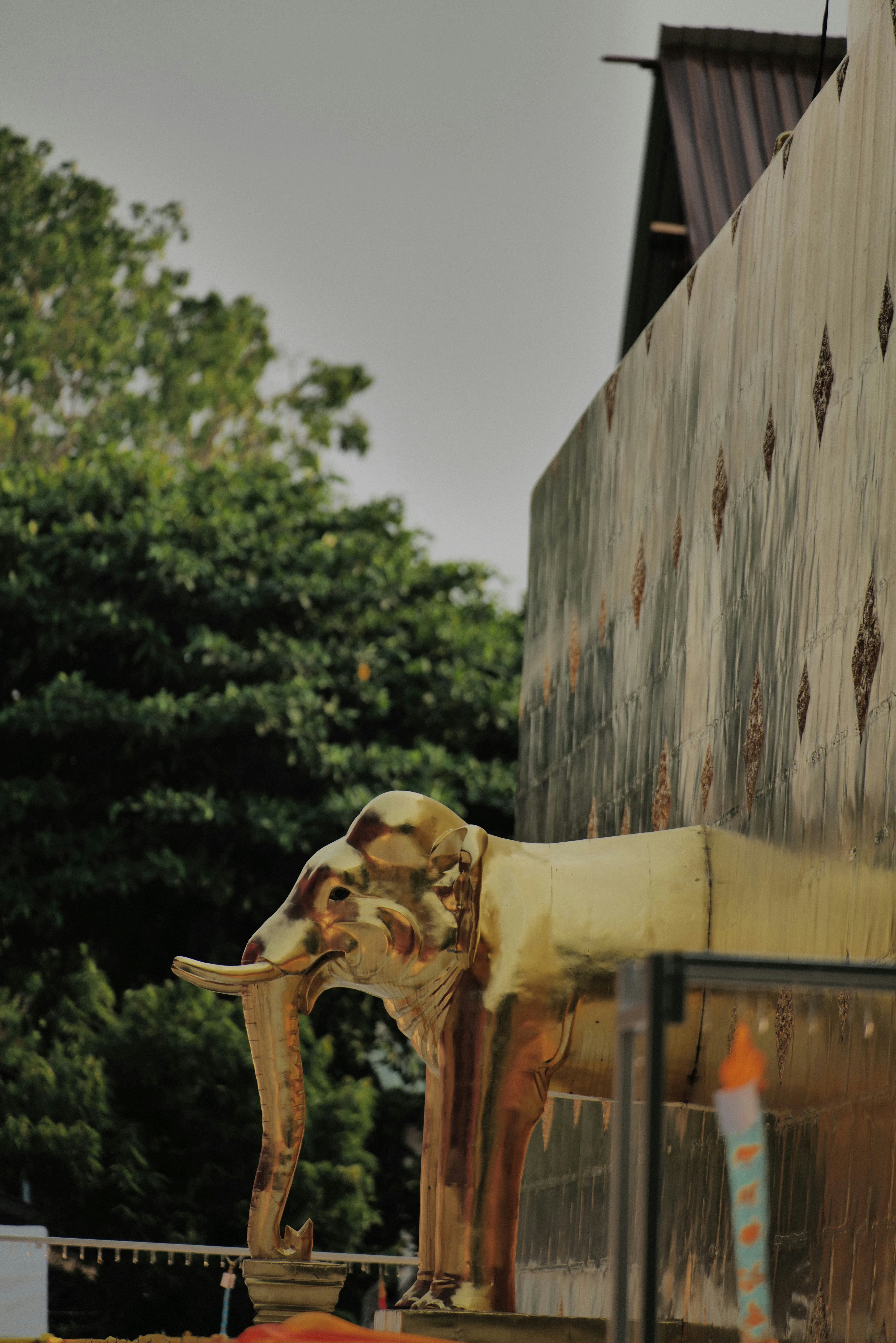 A golden elephant statue stands beside a wall.