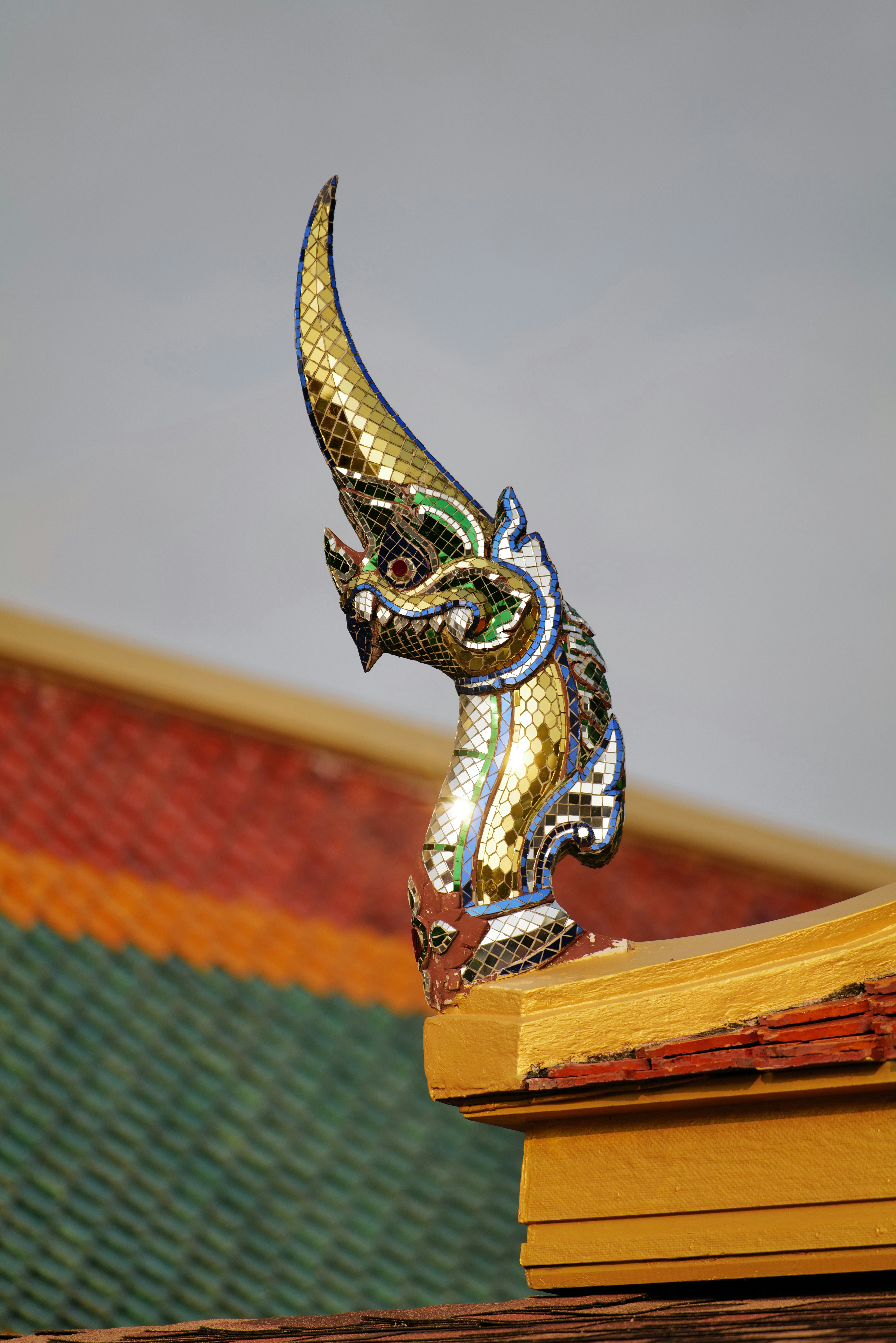 Intricate decorative sculpture atop a temple roof, showcasing vibrant colors and detailed craftsmanship.