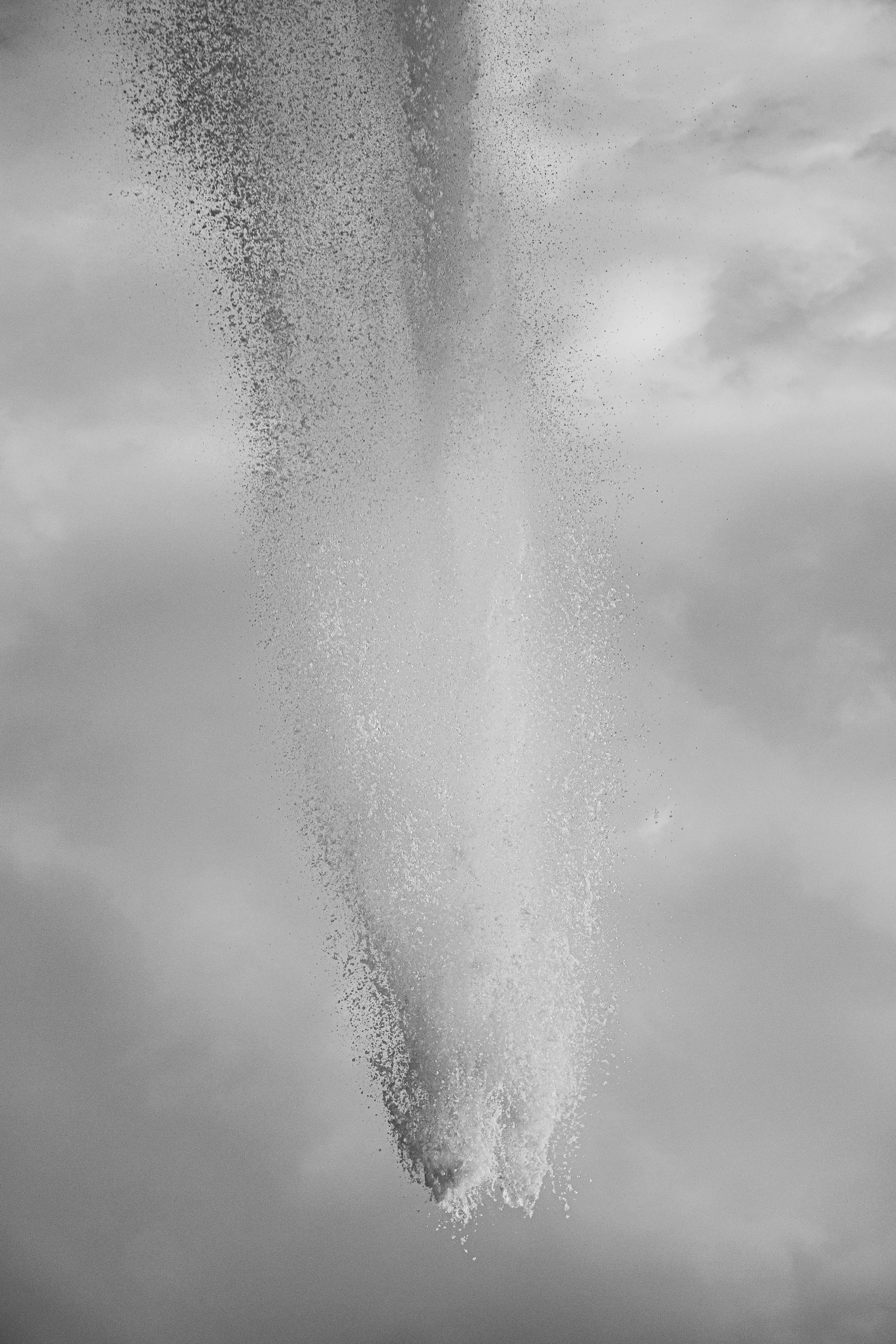 Column of Spray: A Monochrome Geyser Piercing the Clouded Sky
