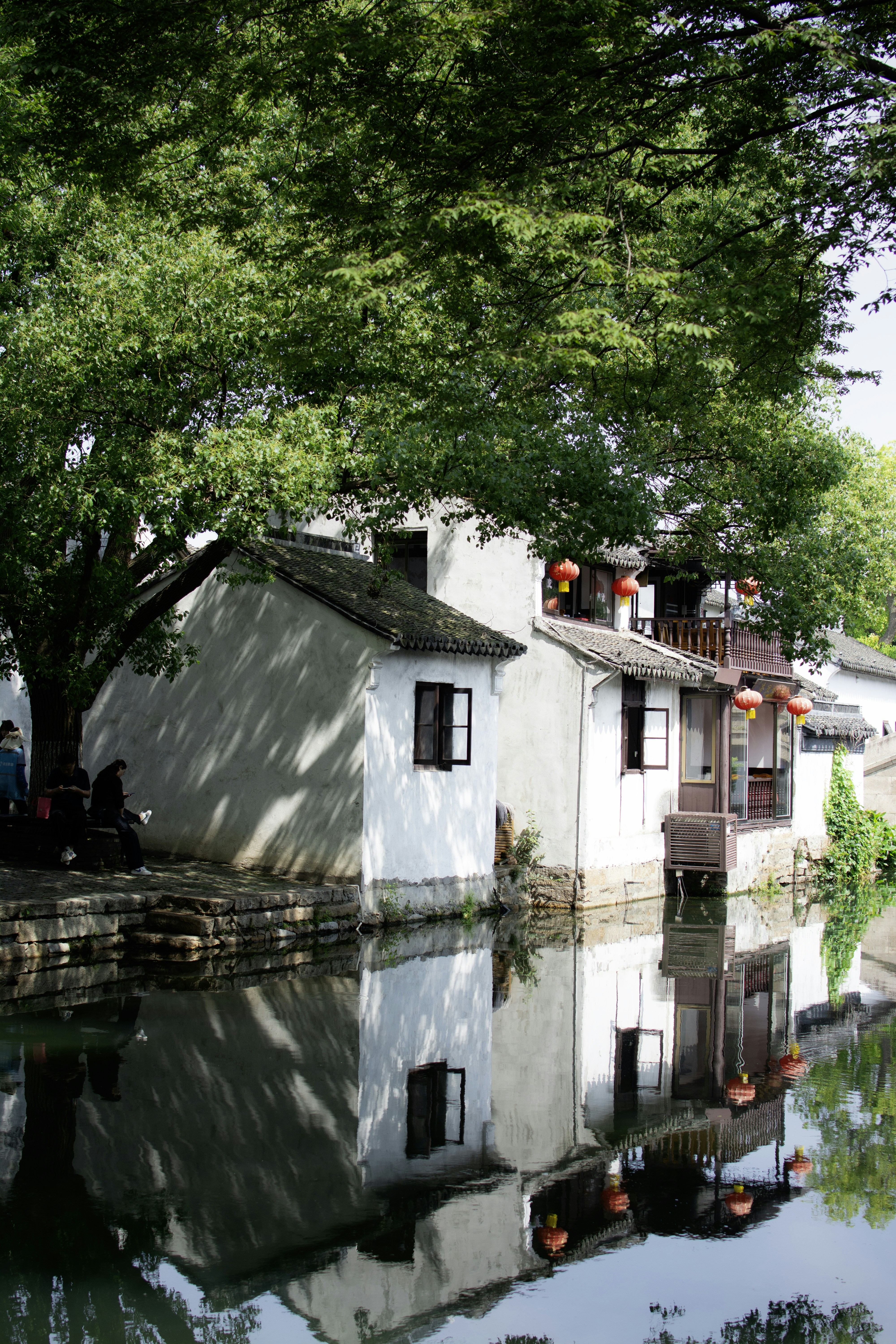 Traditional buildings reflect in the serene water.