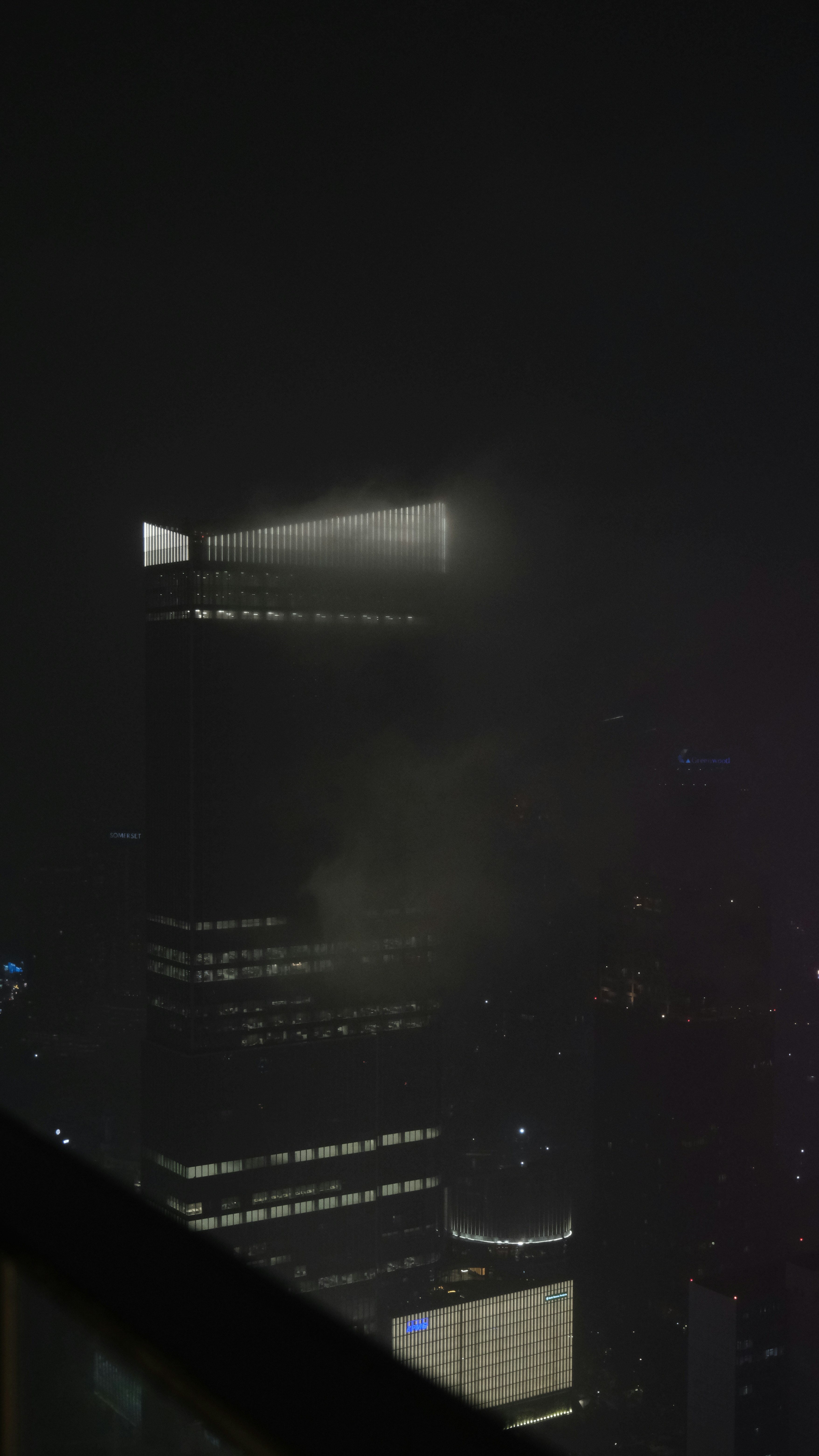 A tall building illuminated at night in fog.