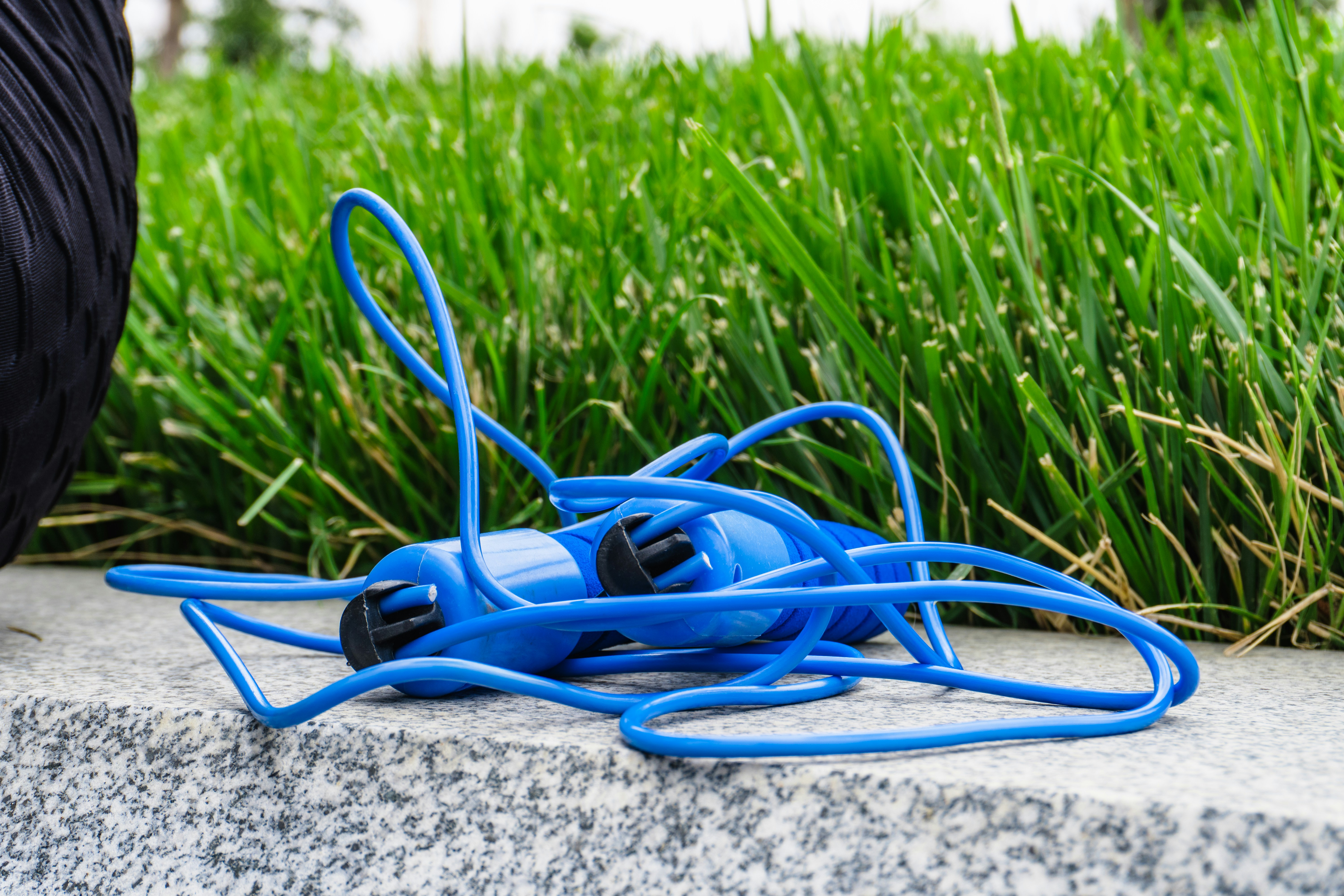 Close-up of a woman holding a blue jump rope, ready for fitness training or a home workout. Concept of healthy lifestyle, sport, activity, and motivation.