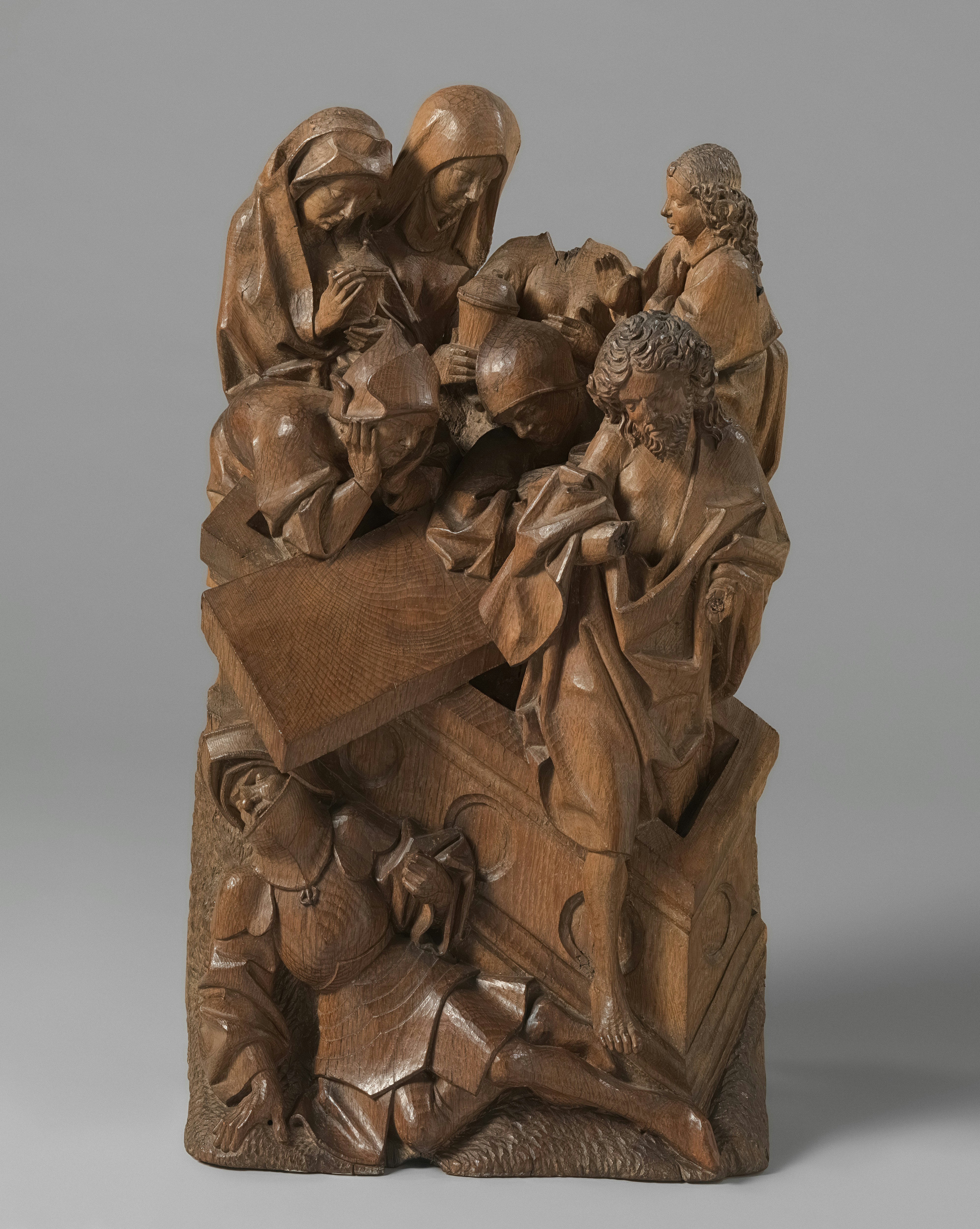 Intricately carved wooden sculpture depicting a poignant scene of mourning, featuring figures in deep contemplation around a central figure. The craftsmanship highlights the emotional depth of the moment.