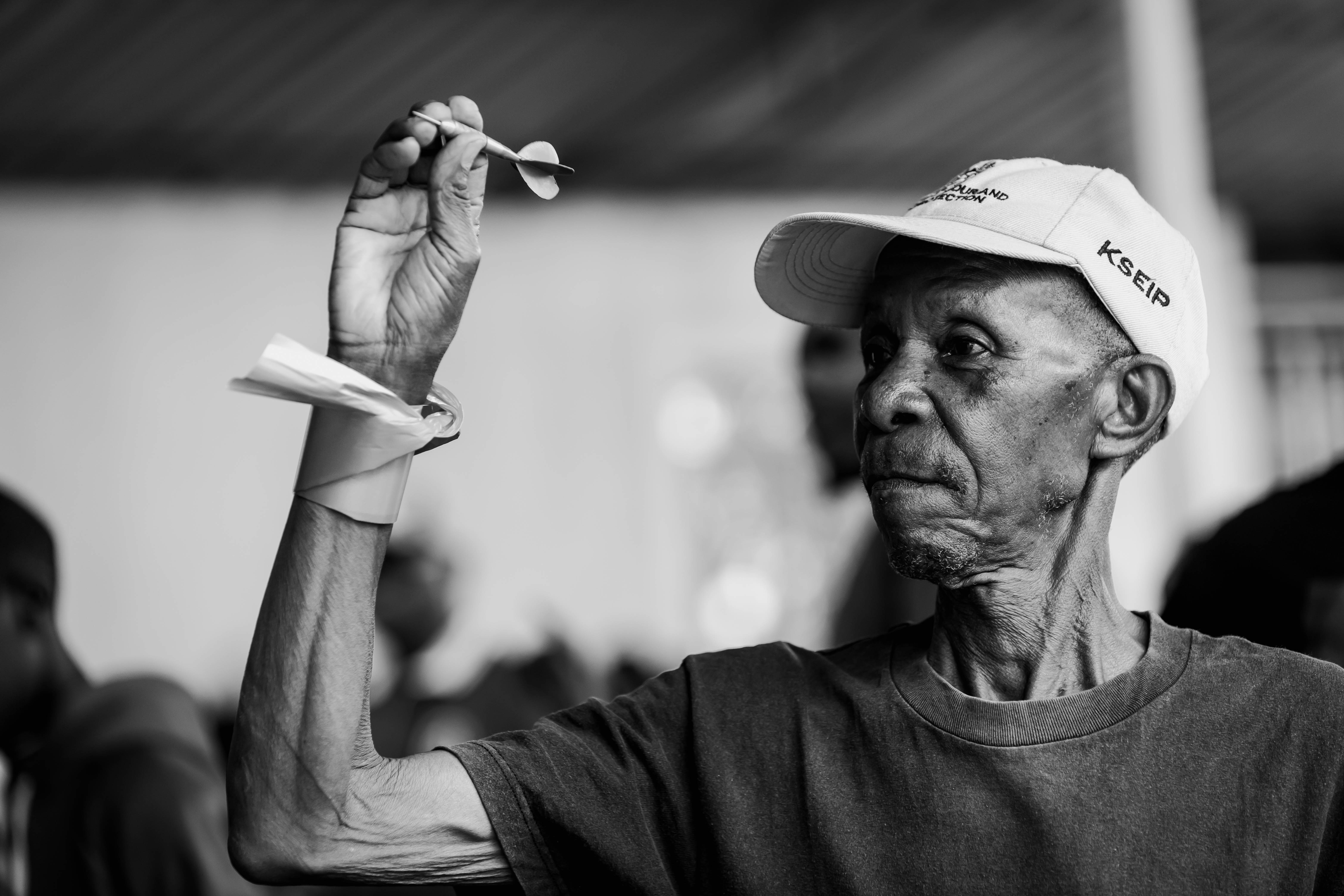 An elderly man is aiming a dart.
