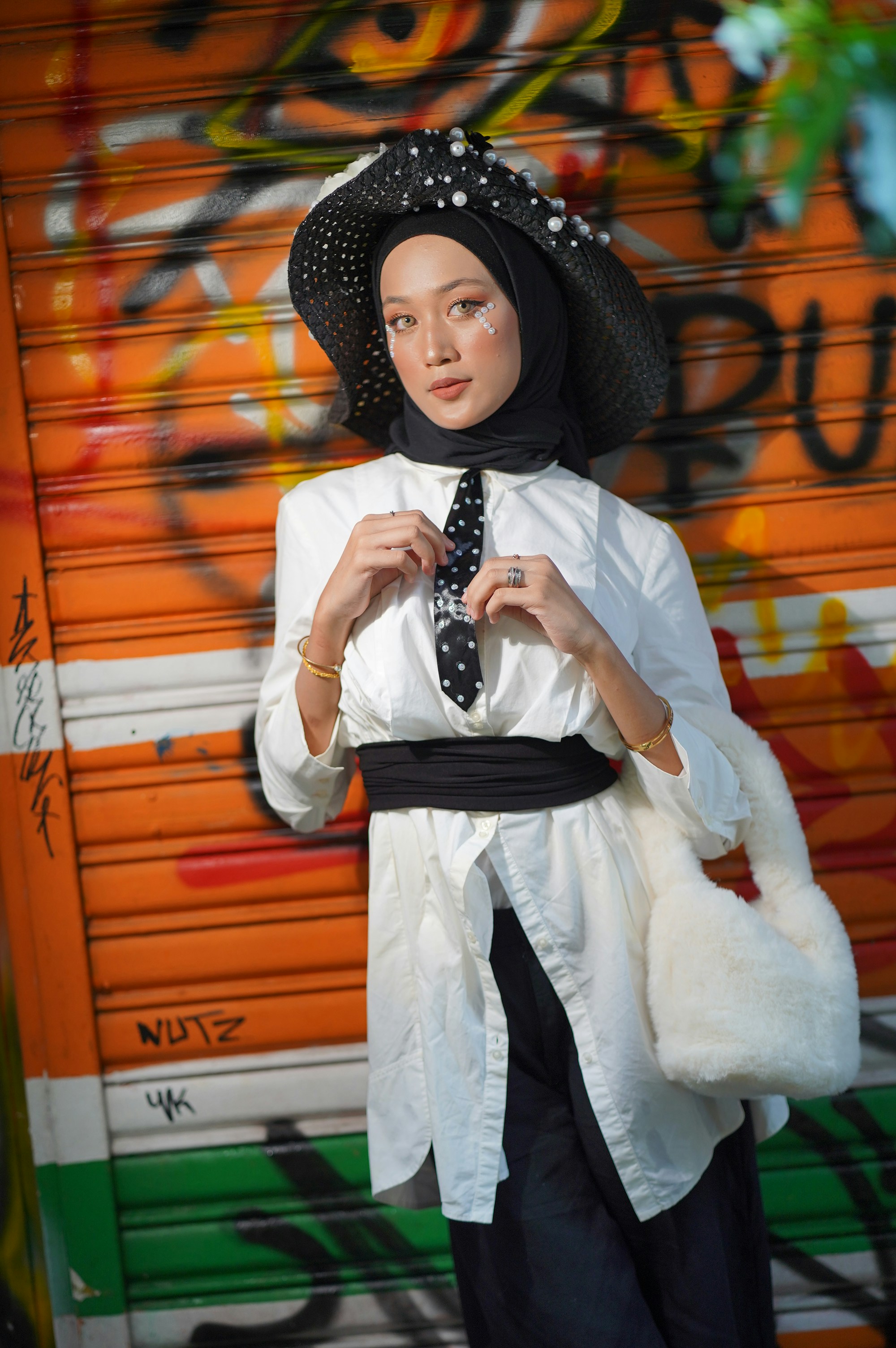 A fashion-forward individual poses against a vibrant graffiti backdrop, showcasing a unique blend of traditional and contemporary styles with bold accessories.