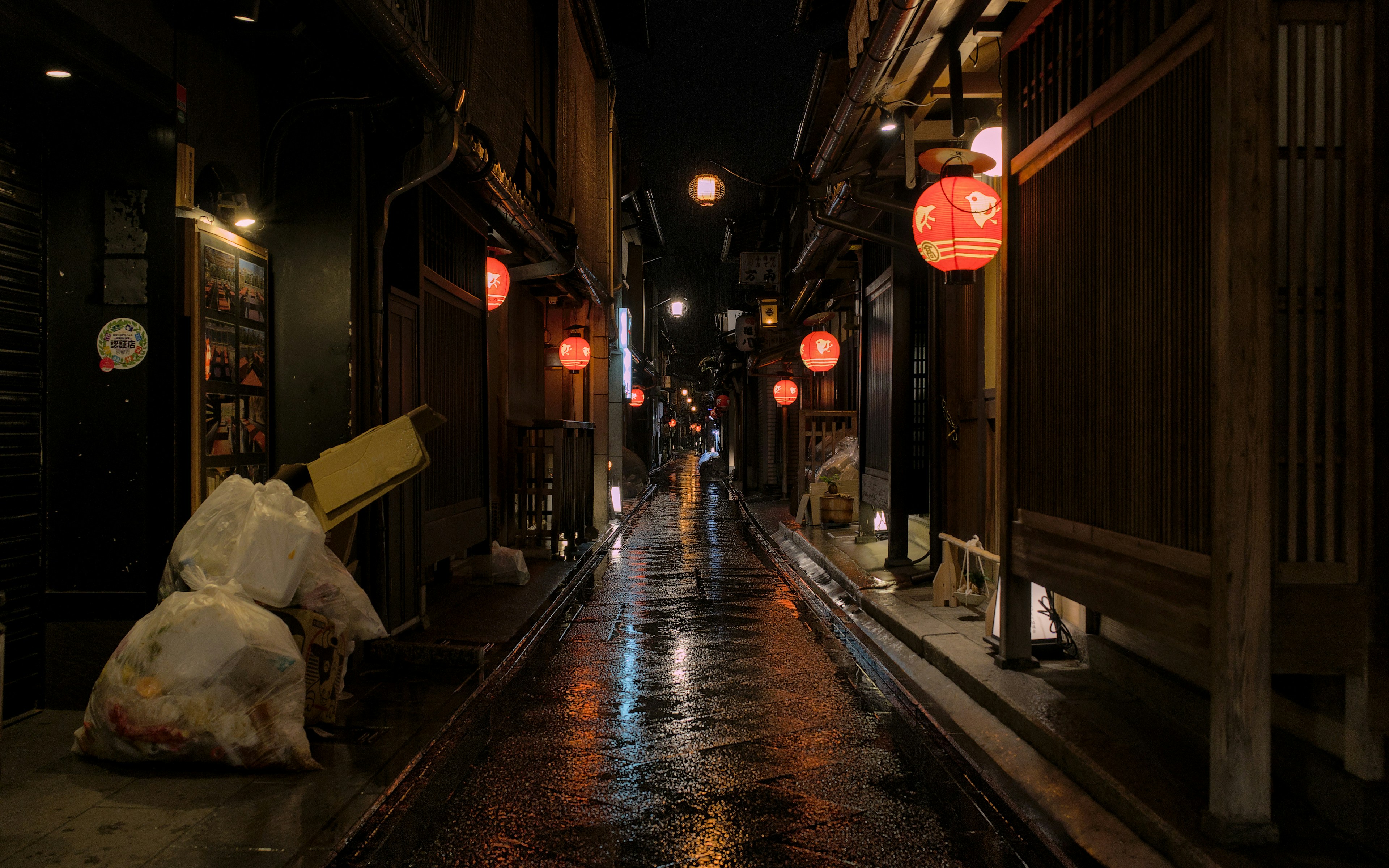 Kyoto's Pontocho Street after midnight, desolate and rainy, with some trash bags in front of a closed restaurant. 2025-05-09